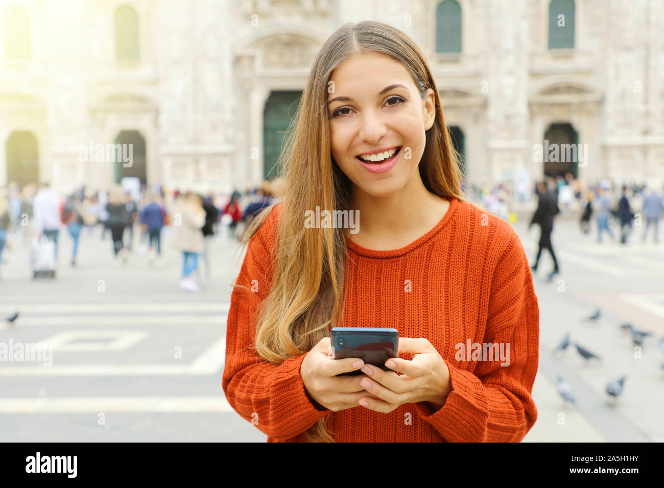 Happy young woman with sweater at good news on her mobile phone looking ...