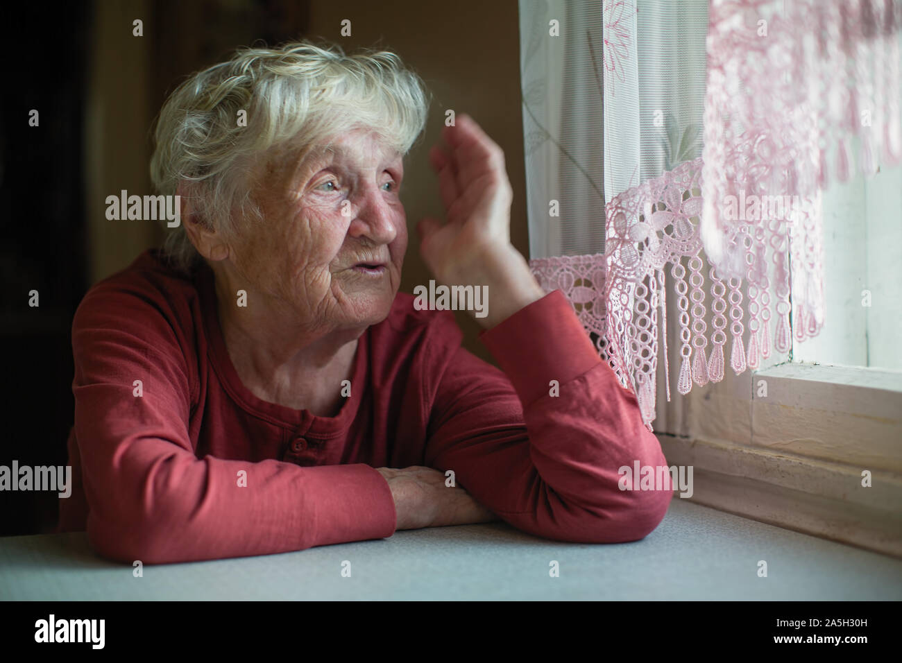 Emotional old lady is sitting at the kitchen table Stock Photo - Alamy