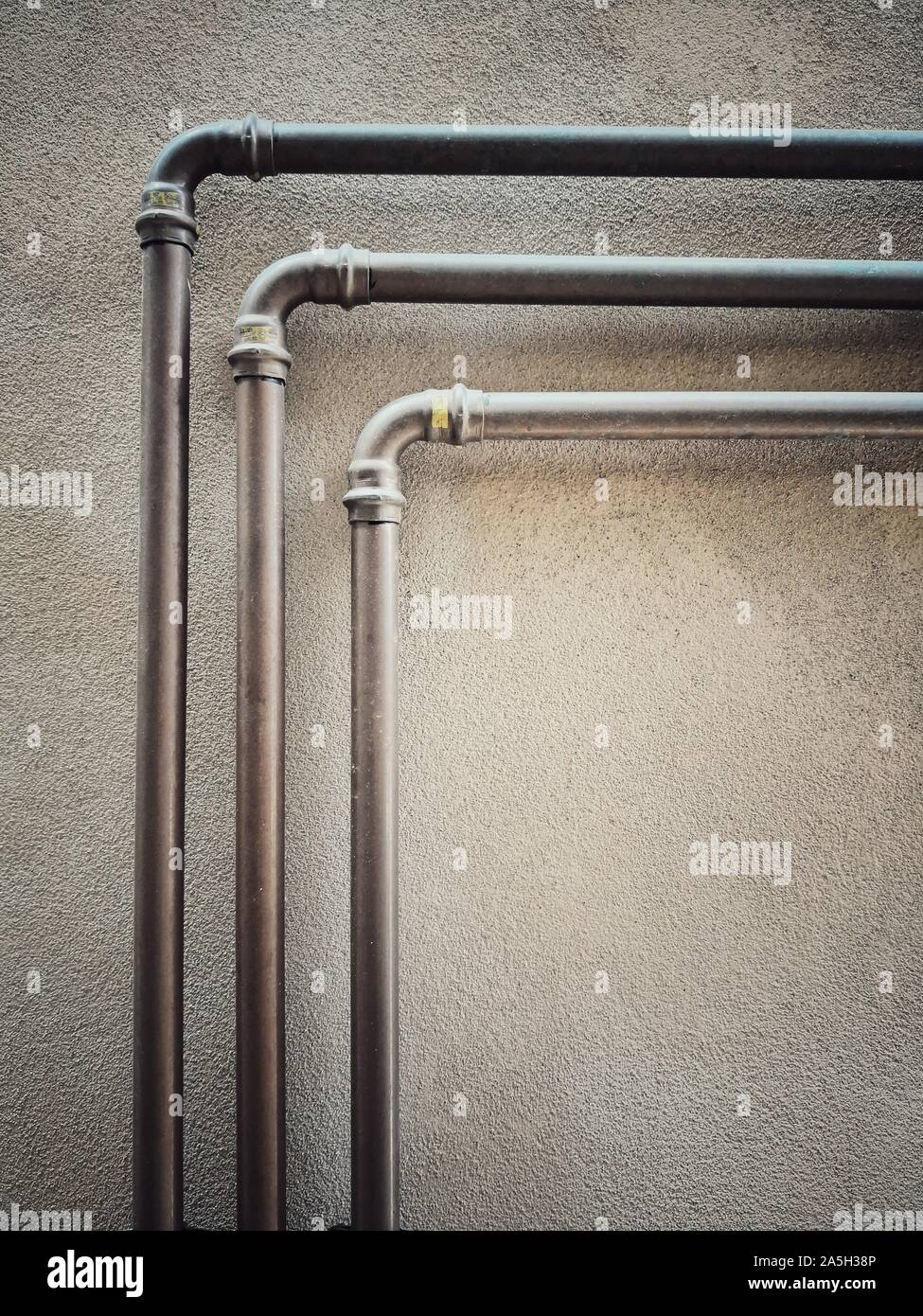 Color image of three pipes at a 90 degree angle, on a wall Stock Photo ...