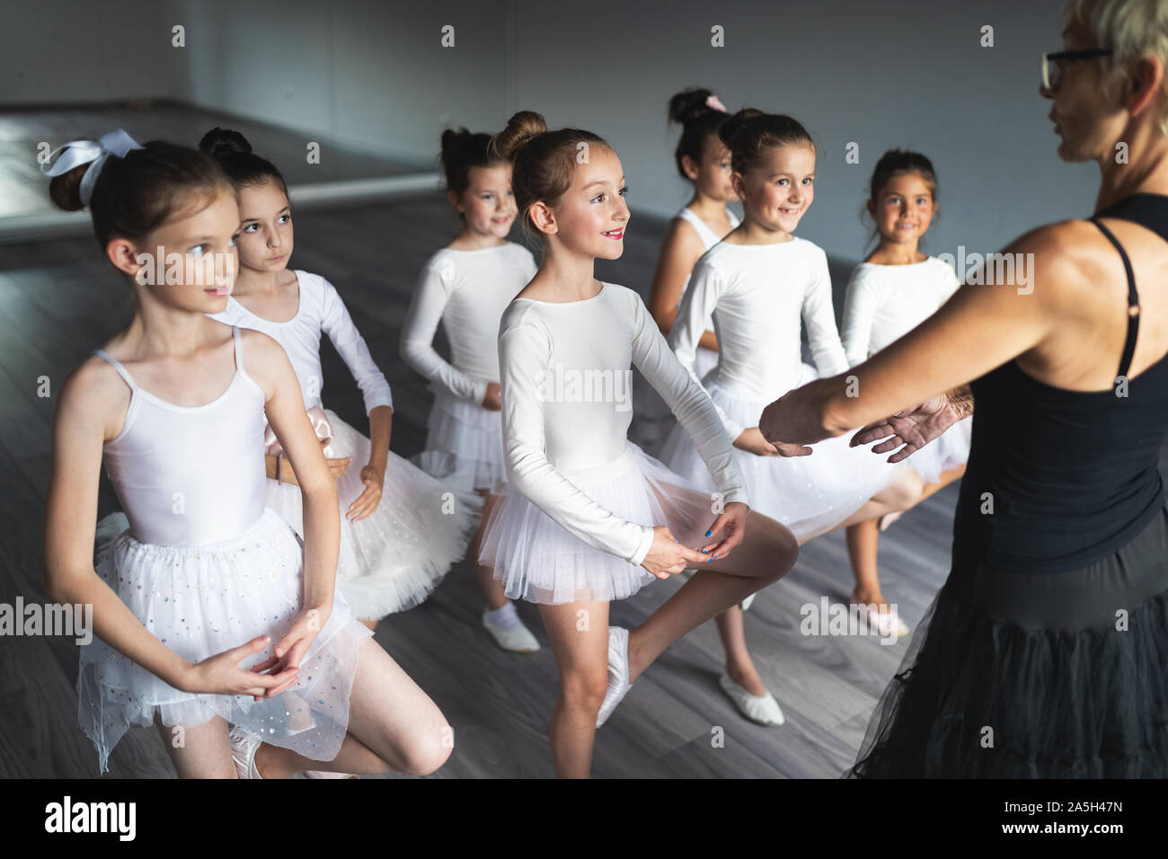 Ballet teacher and students ballerinas exercising in dance class in ...