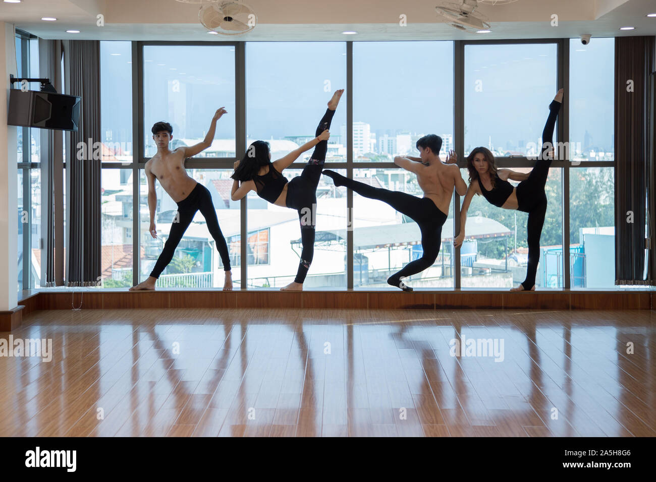 Group of young Asian dancers practicing at ballet bar in hall of dance ...