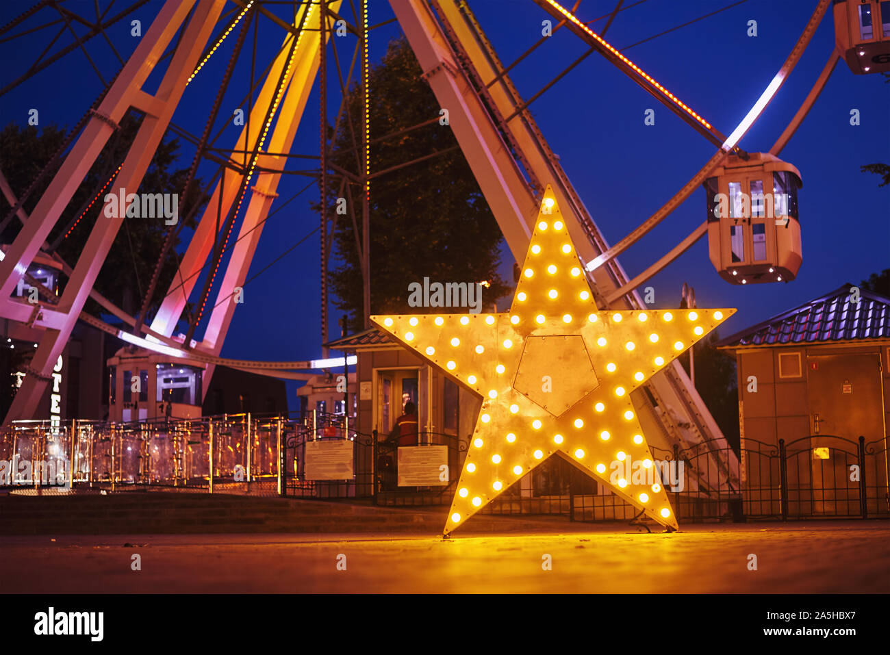 Illuminated glowing star in amusement park at night city Stock Photo ...
