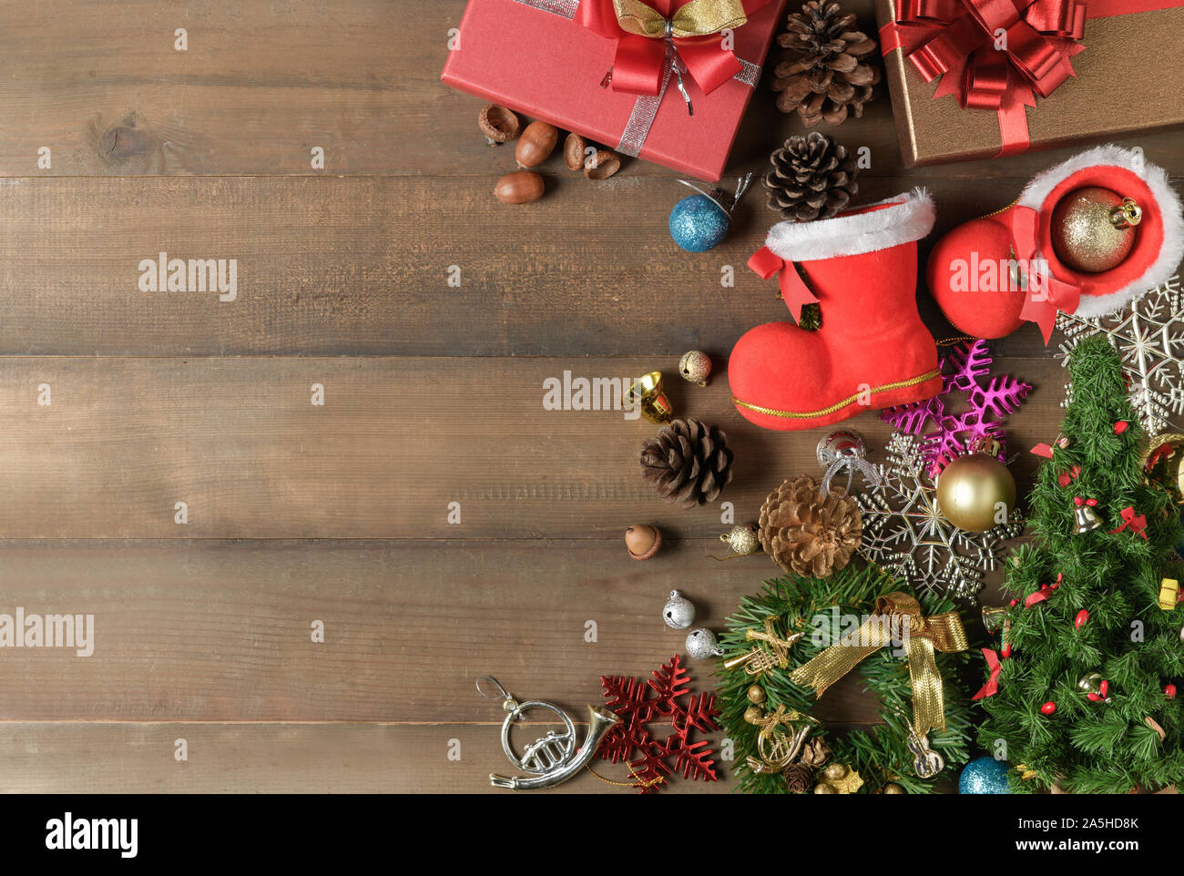 Small santa claus boot with decorations and gift boxes on wooden board ...