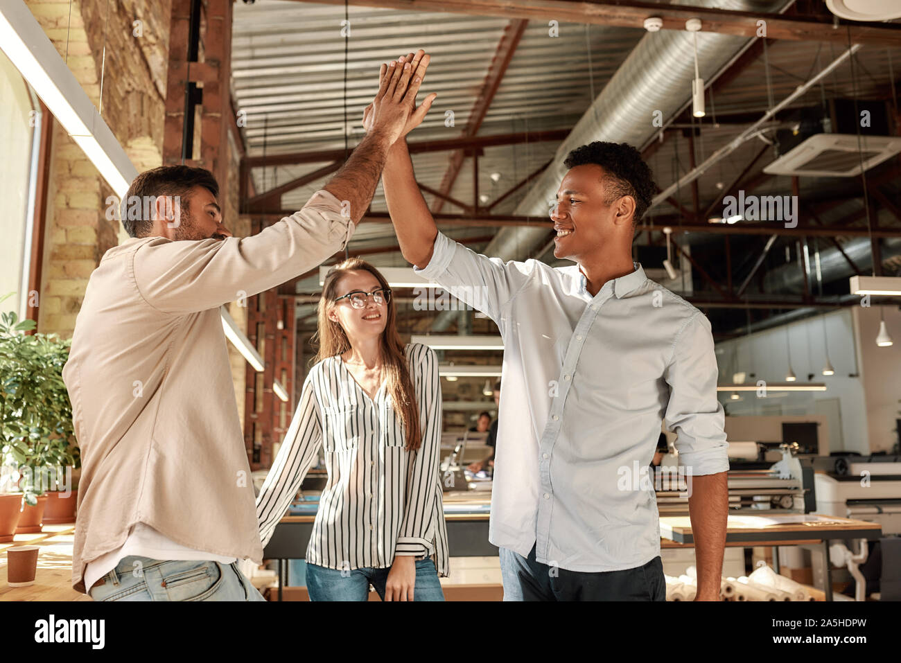 We did it! Two cheerful men giving high-five while standing with ...