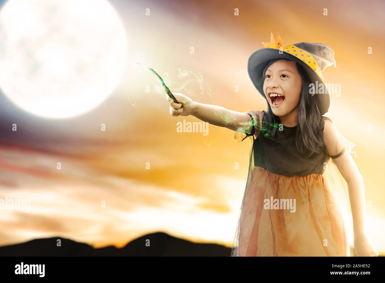 Asian witch little girl using the wand with a magic shine with ...