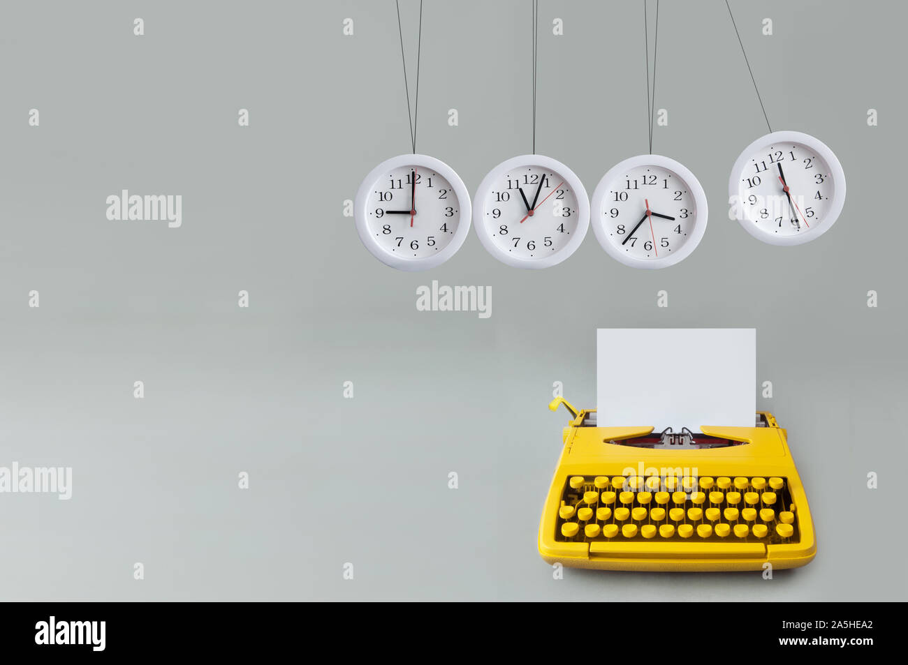 Clocks colliding against each other over a typwriter, work stress ...