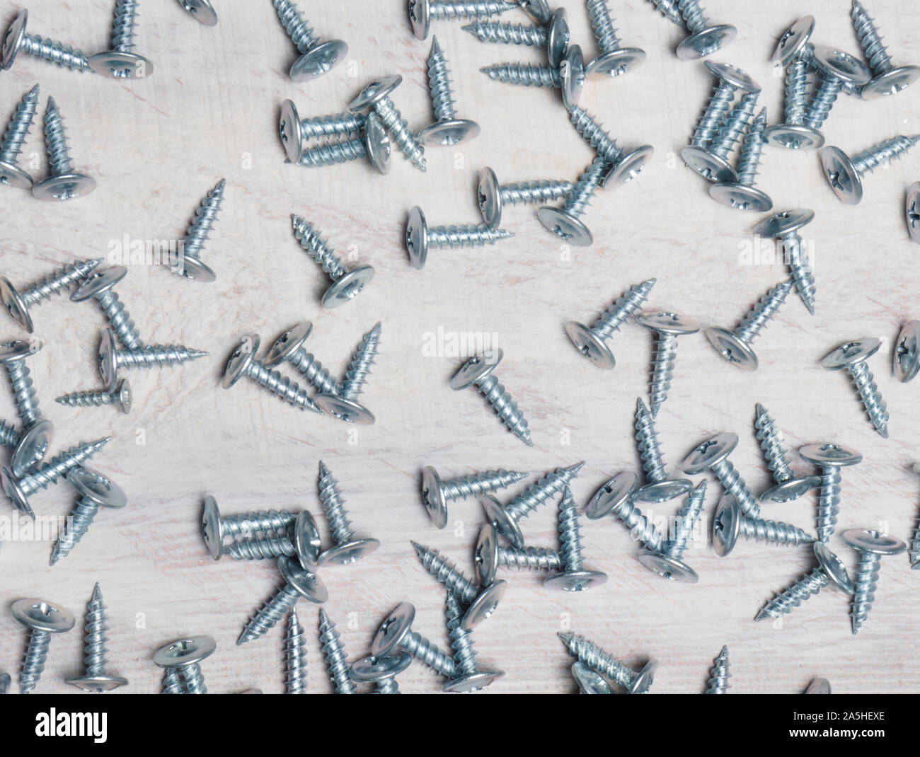 Set of steel silver color screws on light brown background. Industrial ...