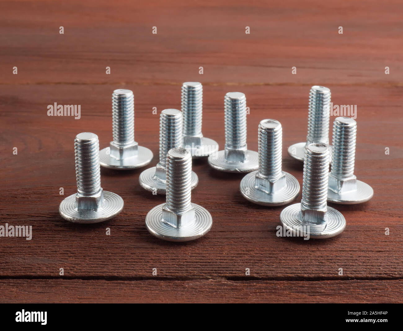 Group of silver color steel screws on brown background Stock Photo - Alamy