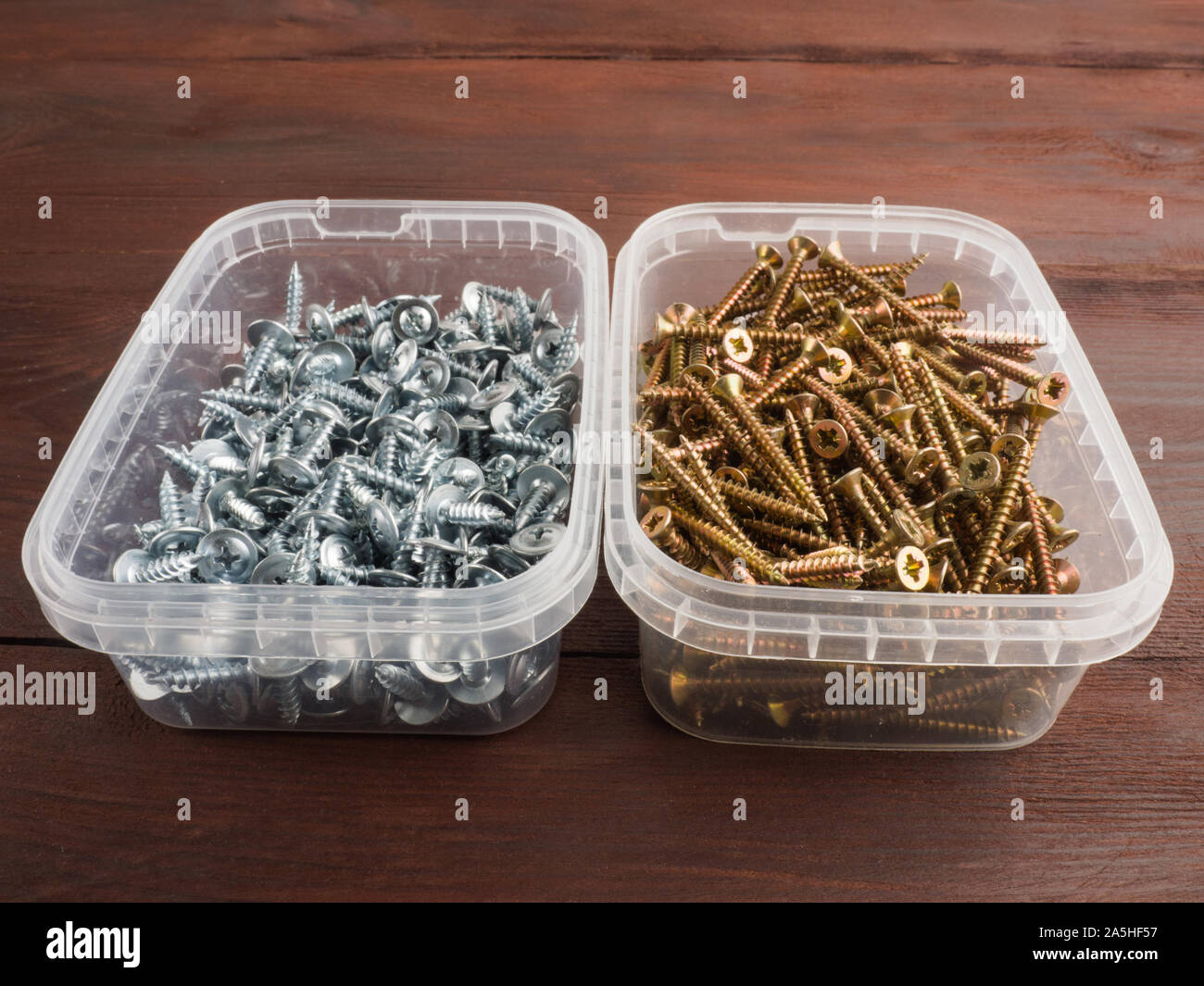 Group of silver color steel screws in two, box, on brown background ...