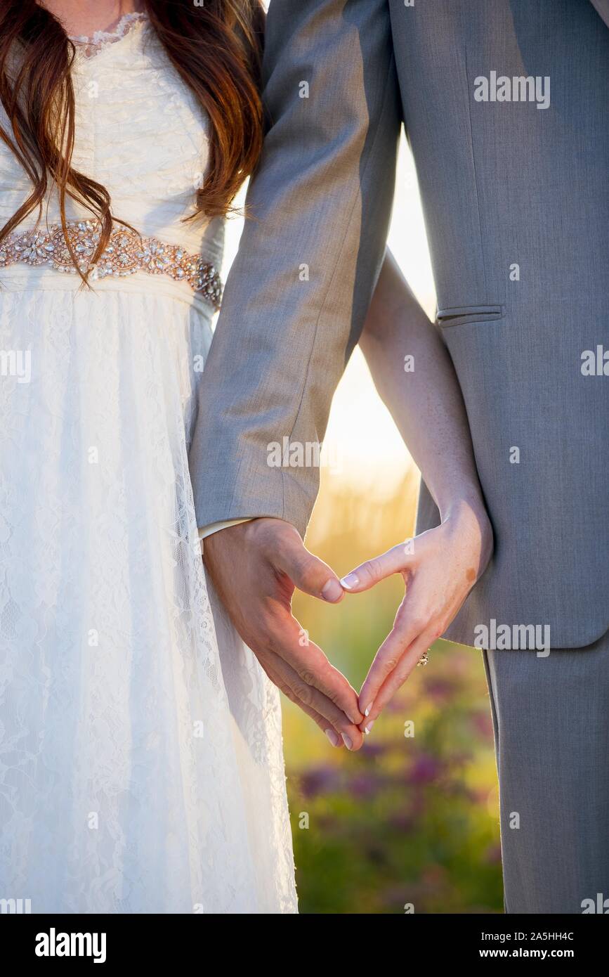 Vertical shot of the bride and the groom making a heart shape with ...
