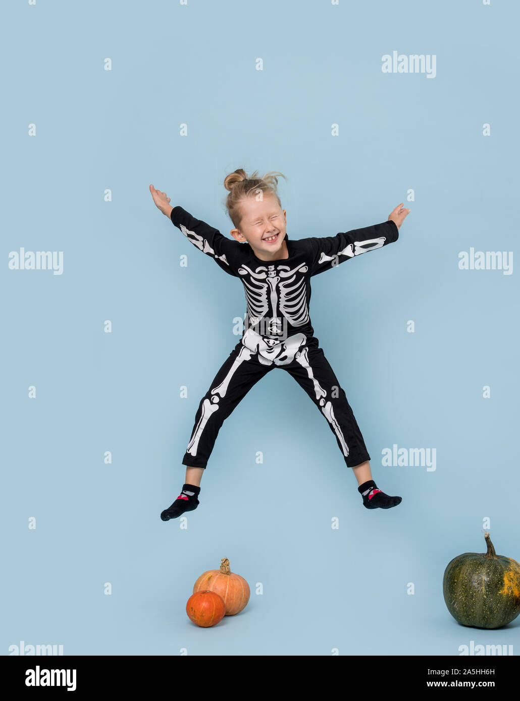 Little boy in skeleton costume jumping in the air with his eyes closed ...
