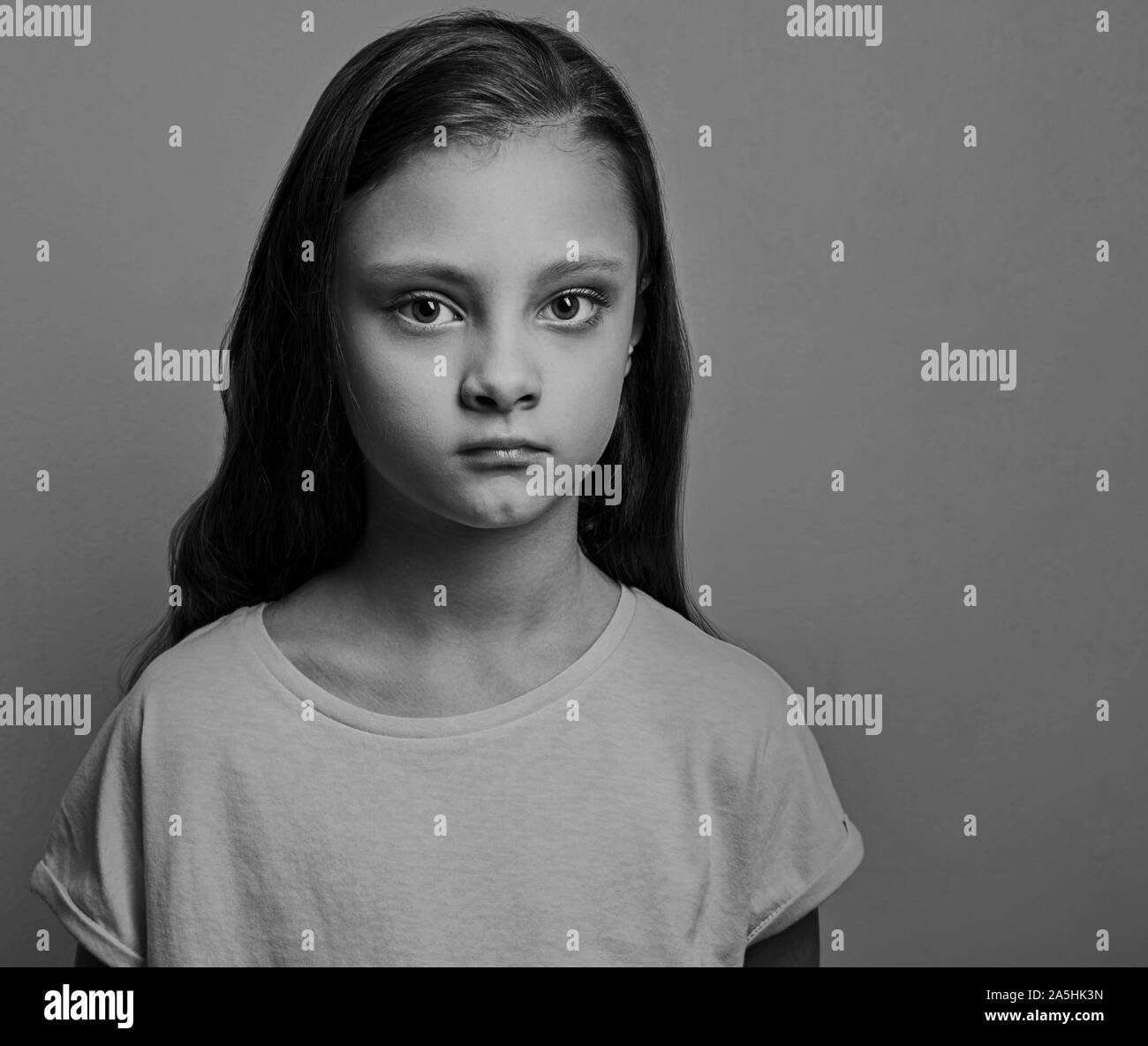 Angry sad kid girl with serious emotions looking on dark background ...