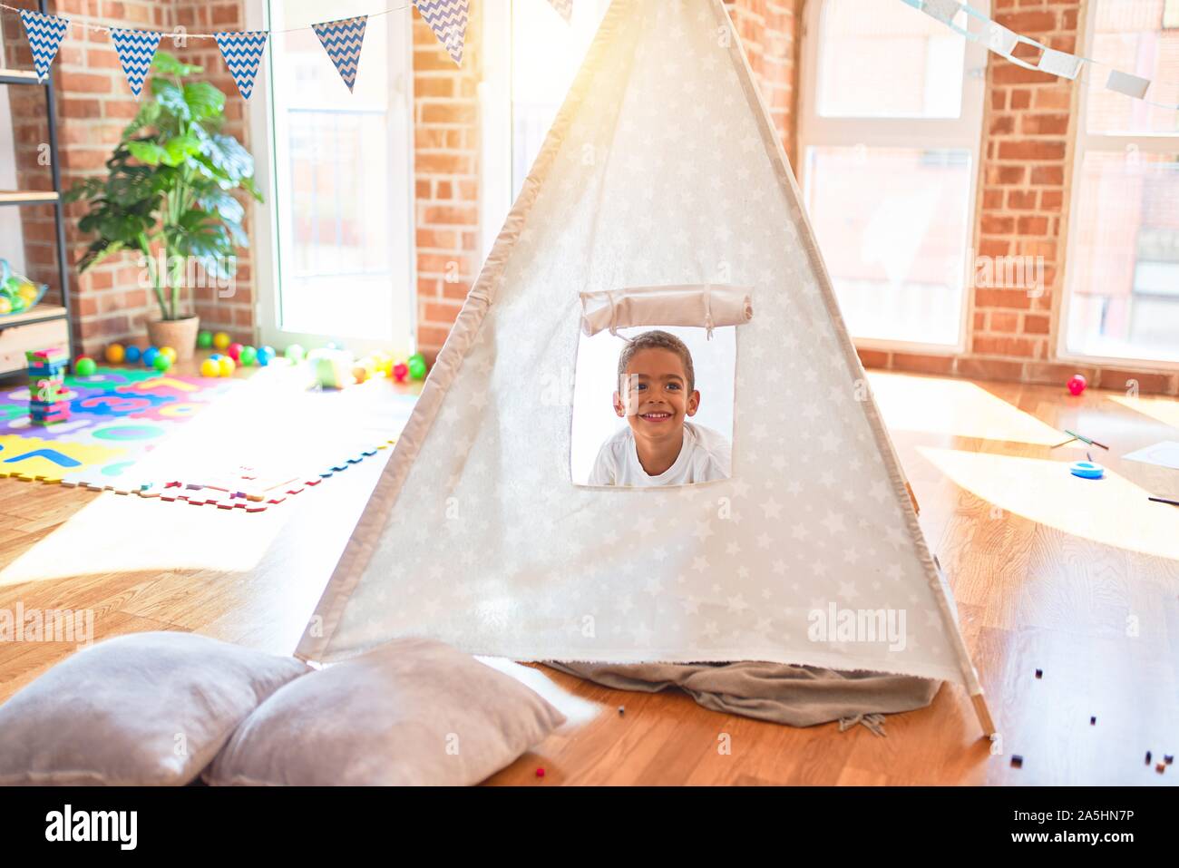 Beautiful african american toddler playing inside tipi smiling at ...