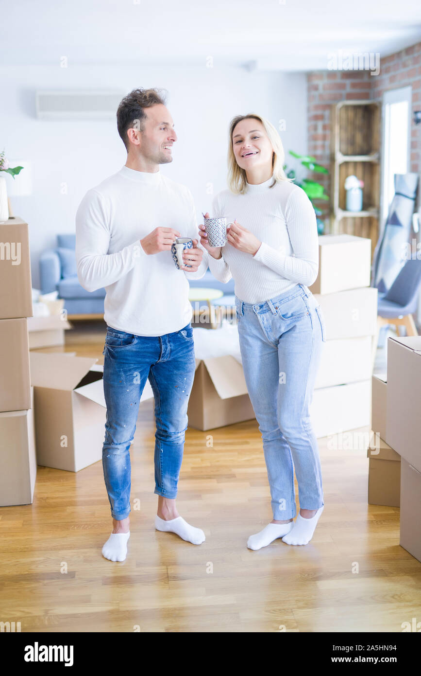 Young Beautiful Couple Standing Drinking Cup Of Coffee At New Home