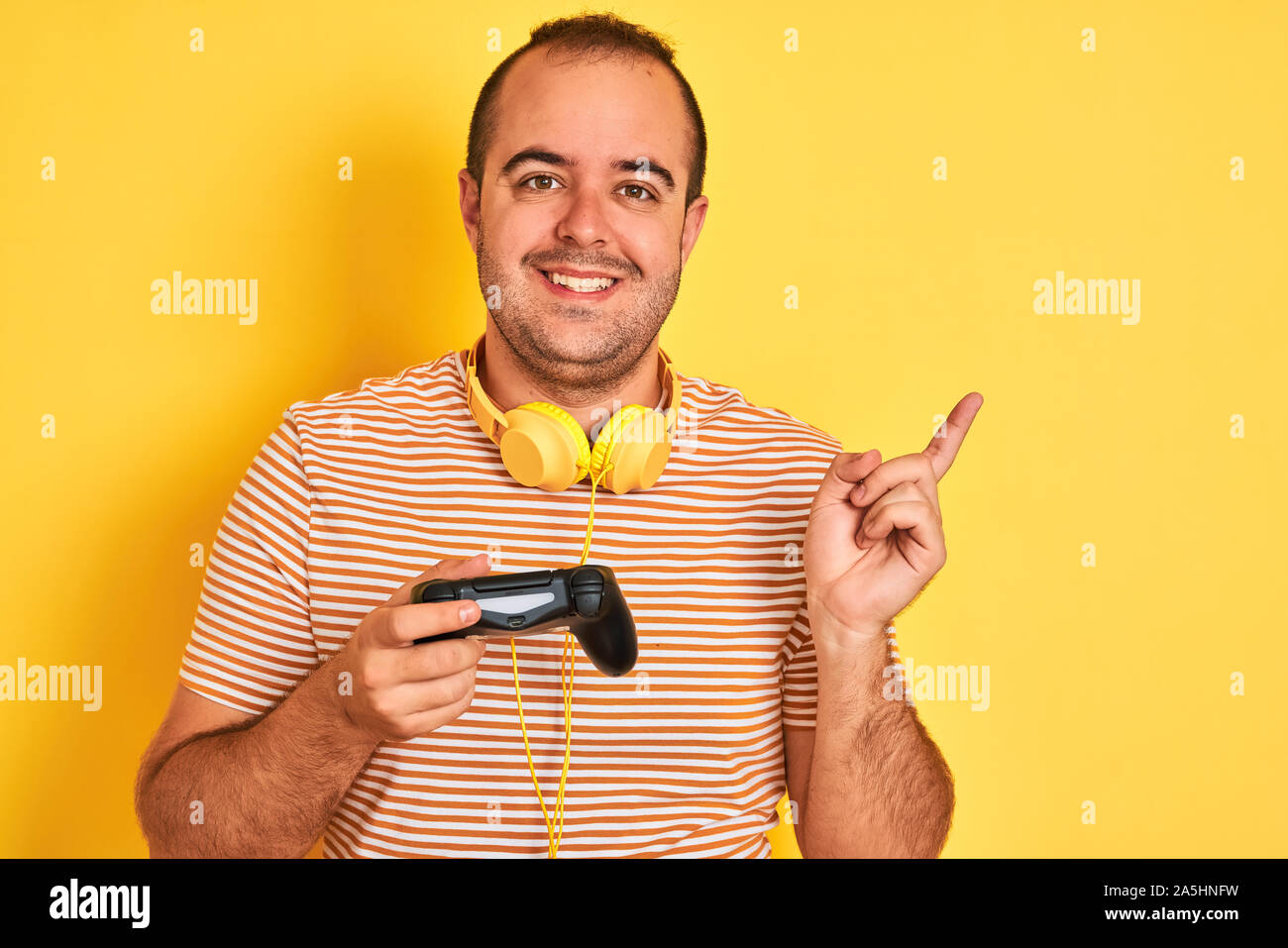 Young gamer man playing video game using headphones over isolated ...