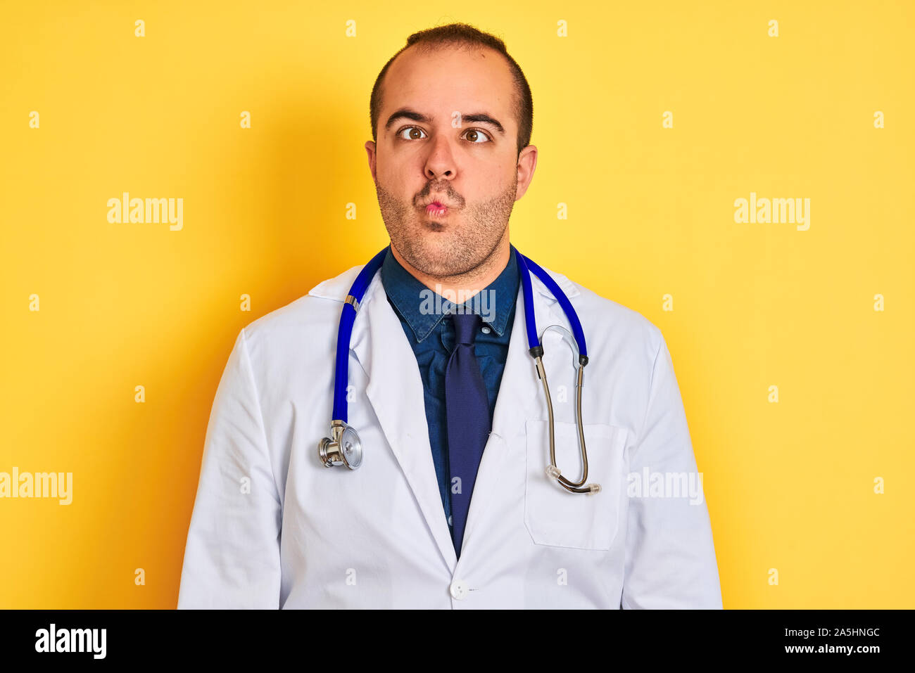 Young doctor man wearing coat and stethoscope standing over isolated ...