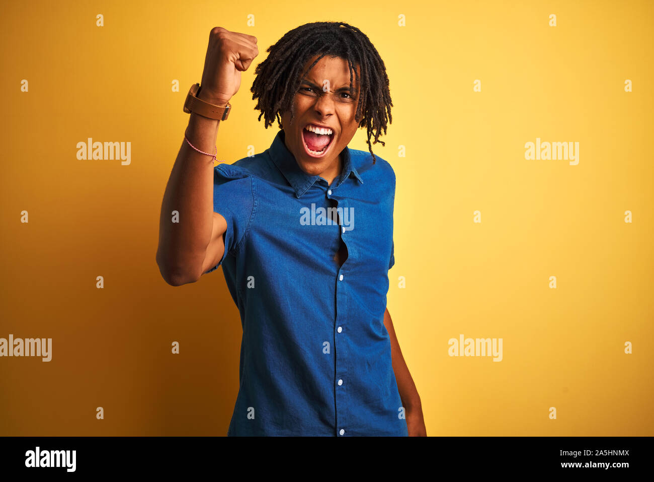 Afro man with dreadlocks wearing casual denim shirt standing over ...