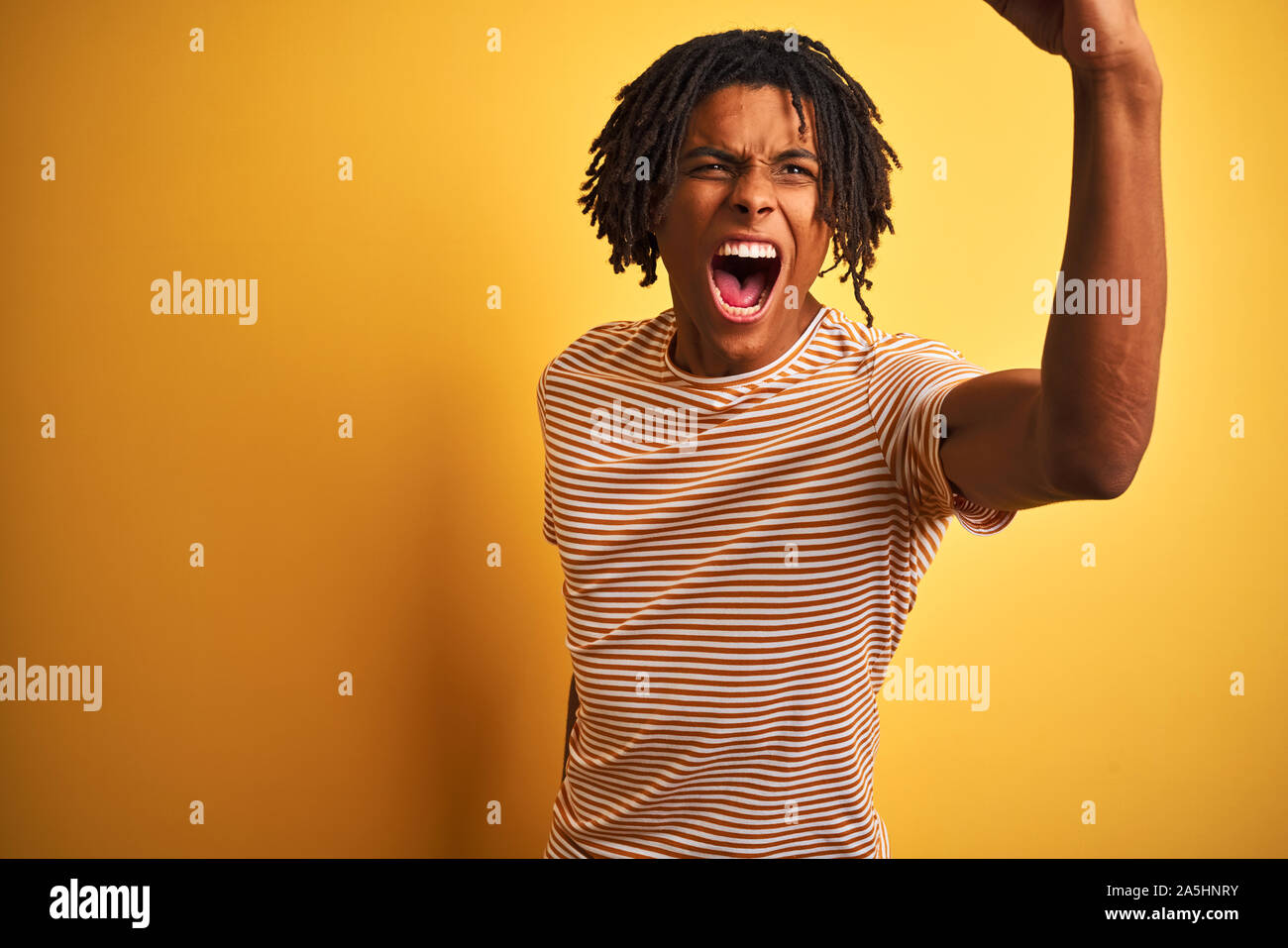Afro man with dreadlocks wearing striped t-shirt standing over isolated ...