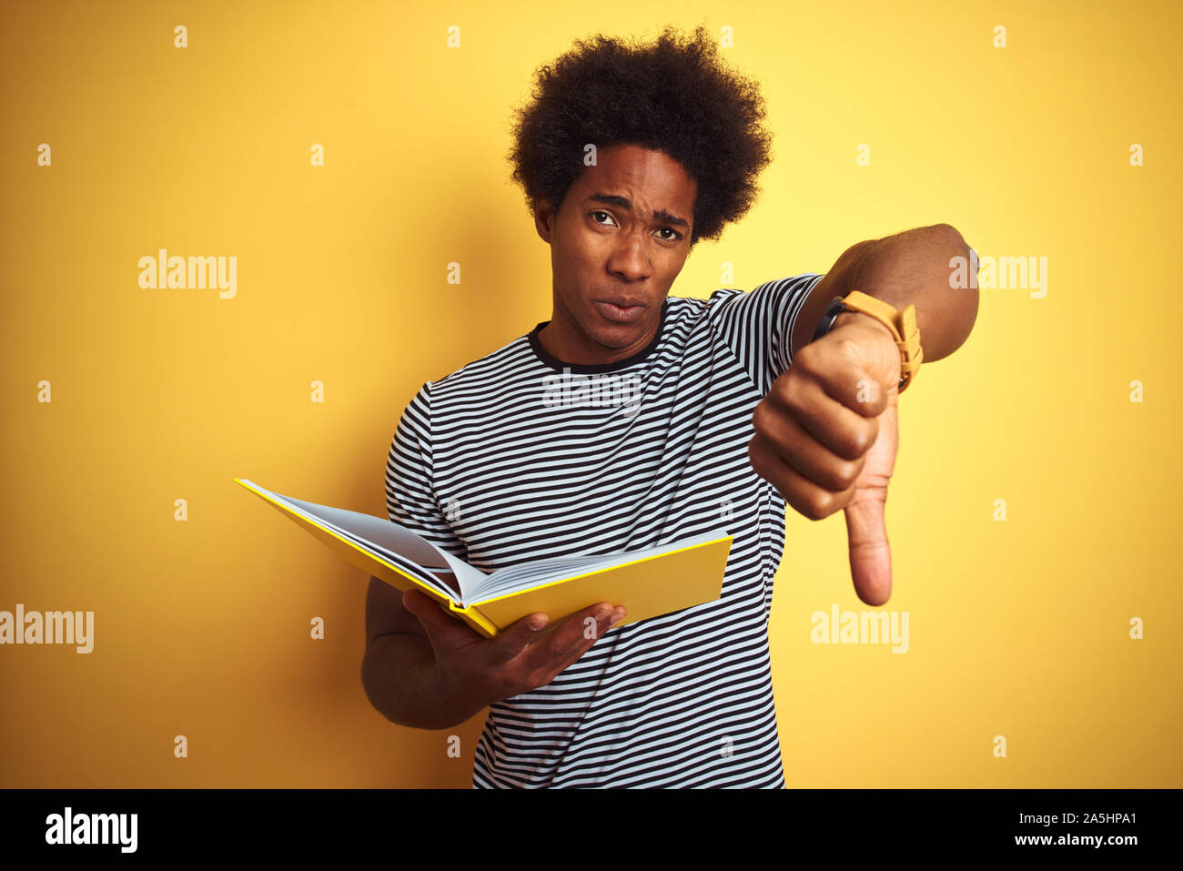 Afro american student man reading book standing over isolated yellow ...