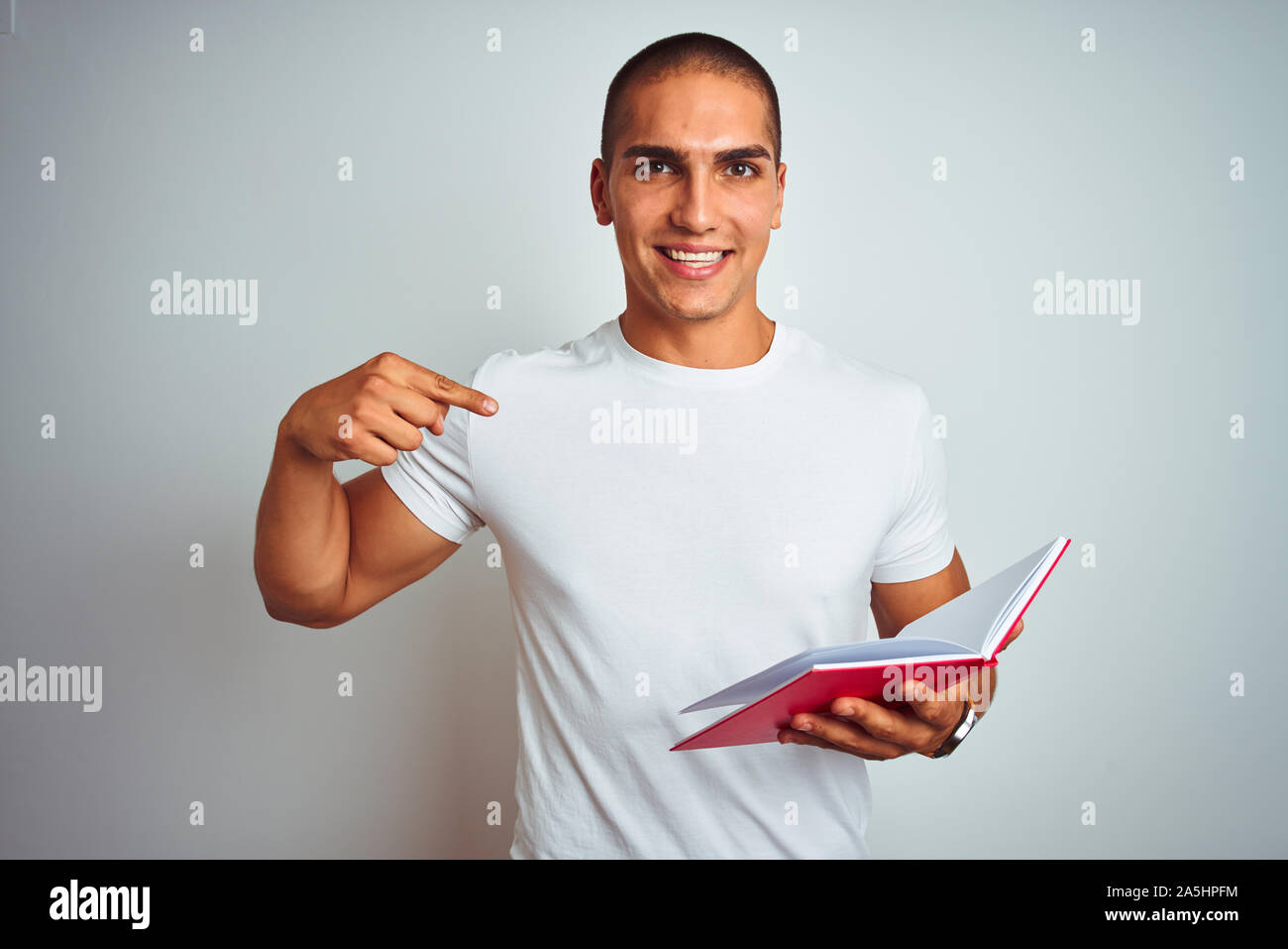 Young handsome man reading red book over white isolated background with ...