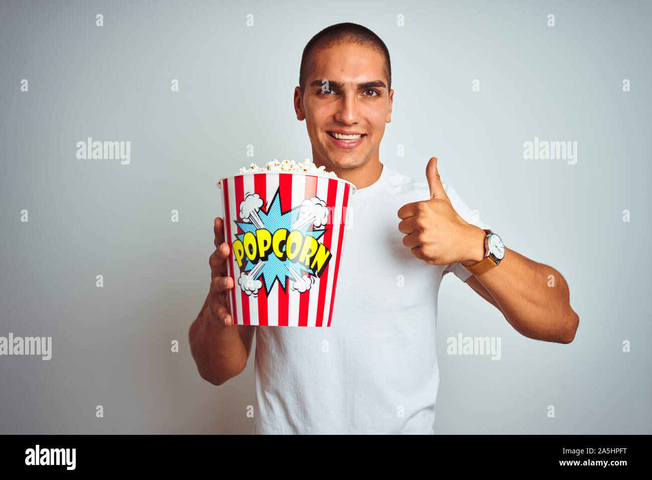 Young handsome man eating popcorn over white isolated background happy ...
