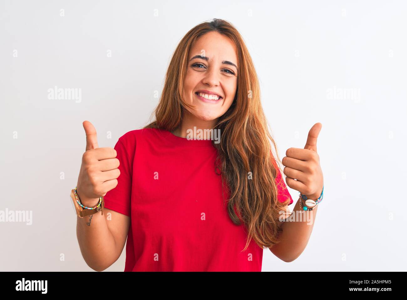 Young redhead woman wearing red casual t-shirt stading over white ...