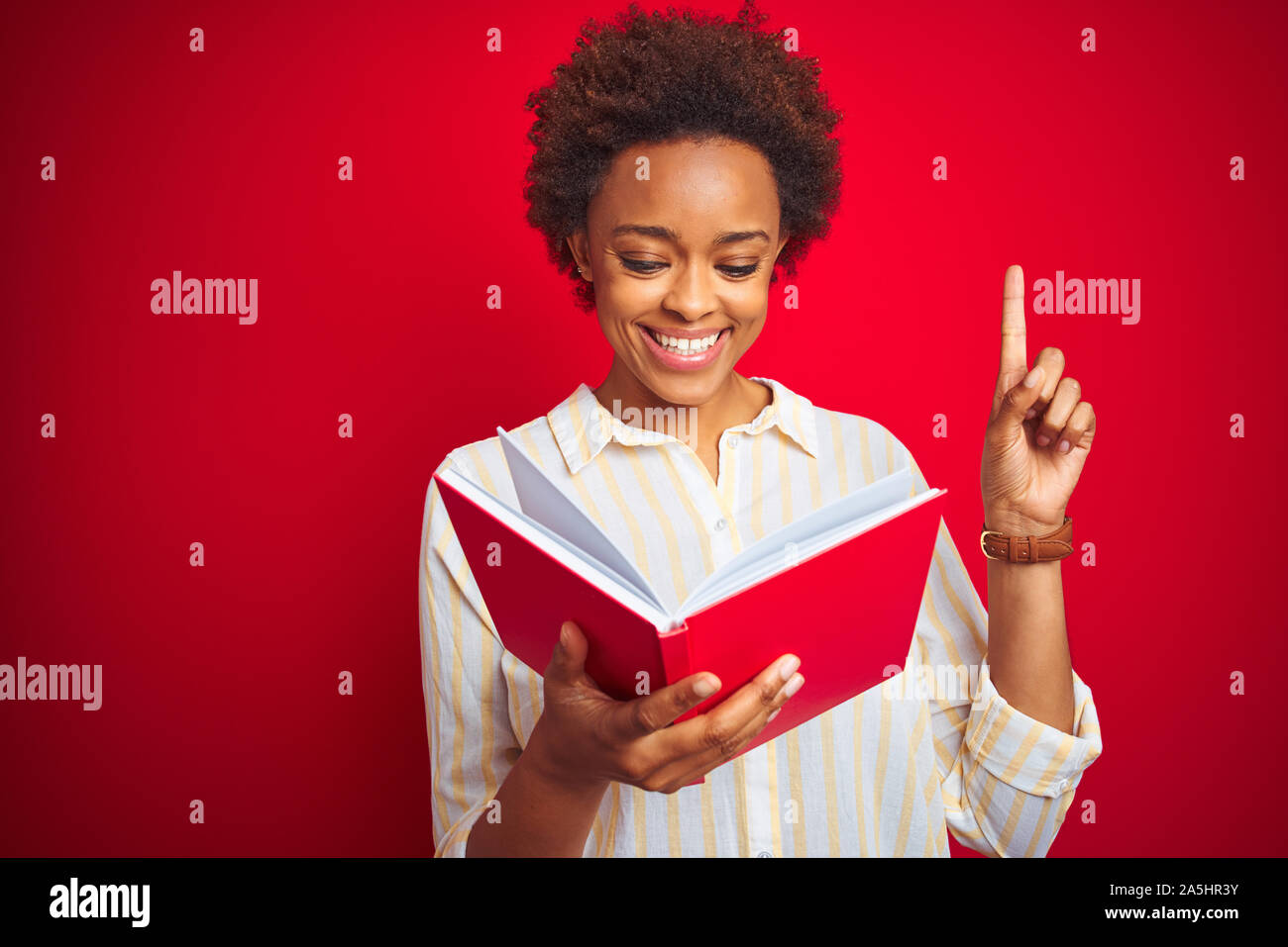 African american woman reading a book over red isolated background ...