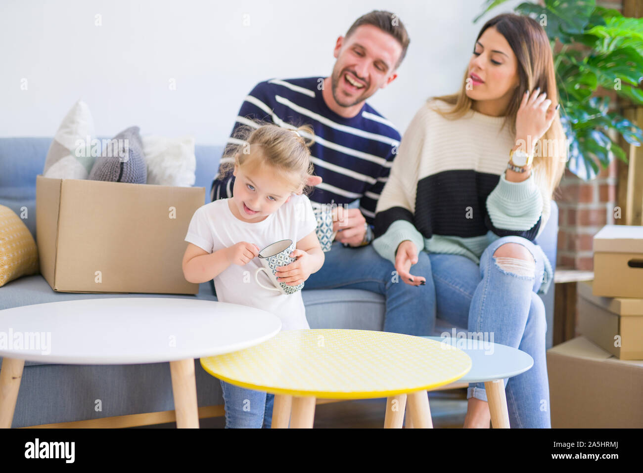 Beautiful family, parents sitting on the sofa drinking coffee looking ...