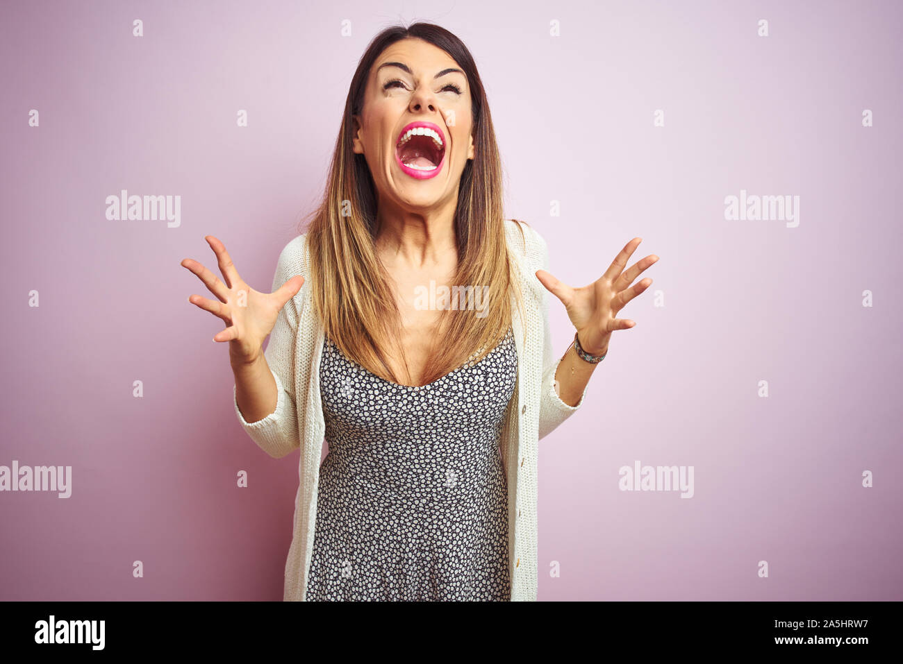 Young beautiful woman standing over pink isolated background crazy and ...