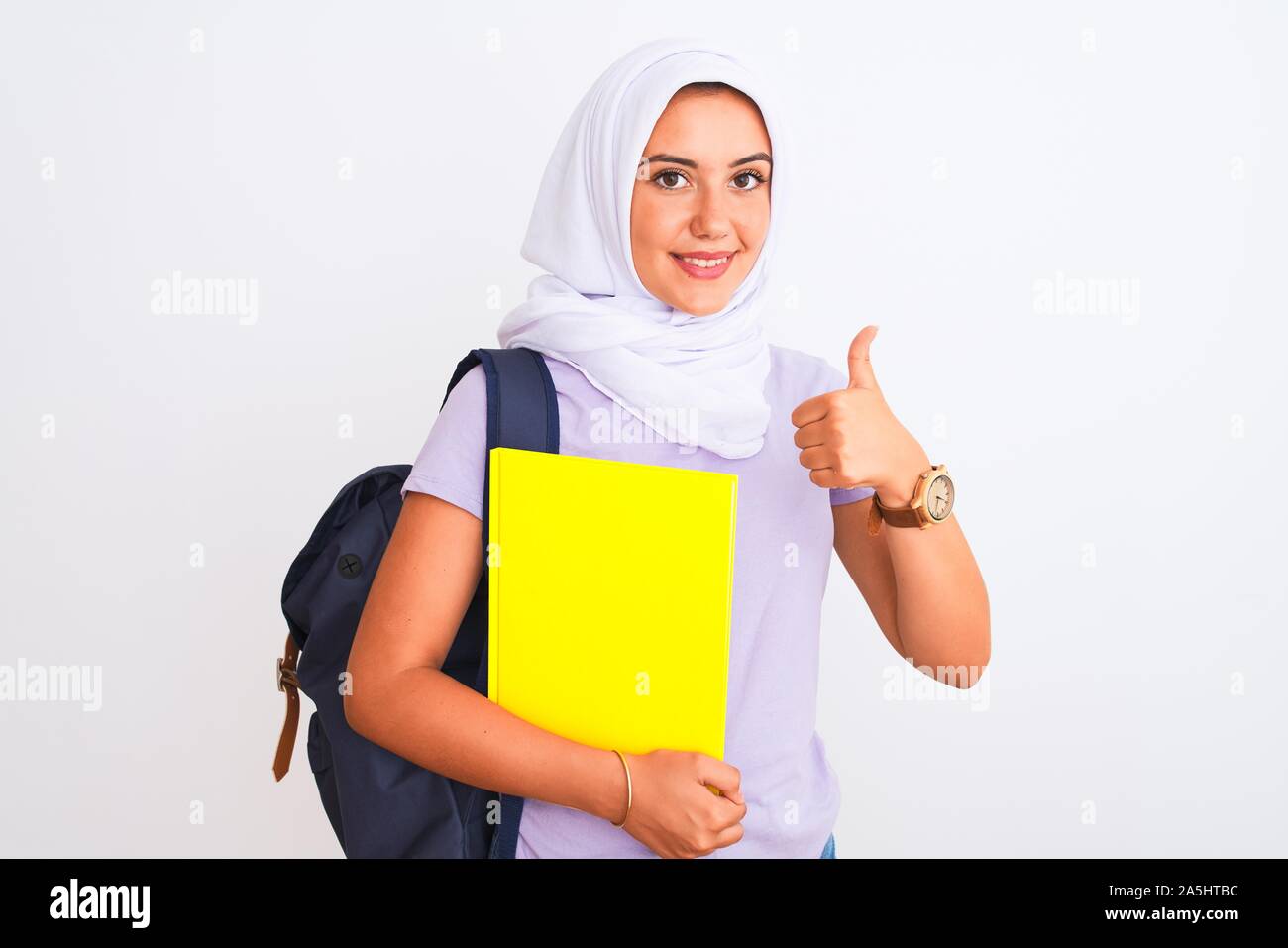 Arab student girl wearing hijab and backpack holding book over isolated ...