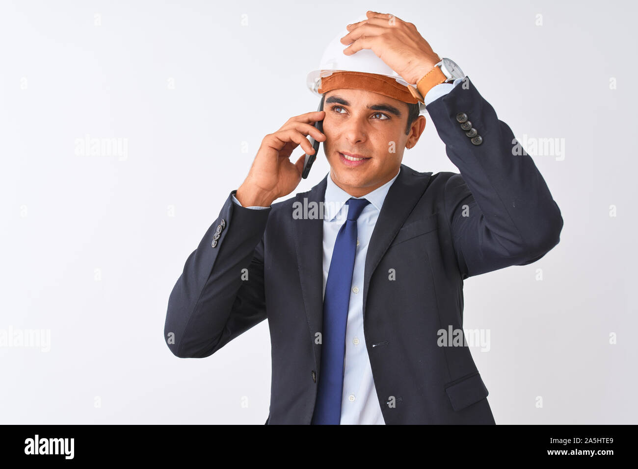 Young architect man wearing helmet talking on smartphone over isolated ...