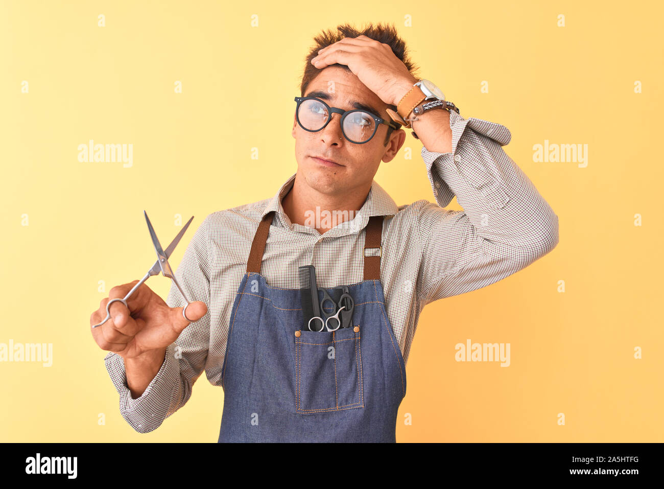 Handsome hairdresser man wearing apron holding scissors over isolated ...