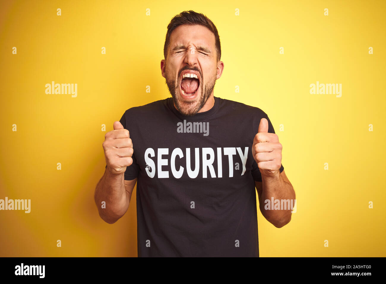 Young safeguard man wearing security uniform over yellow isolated ...