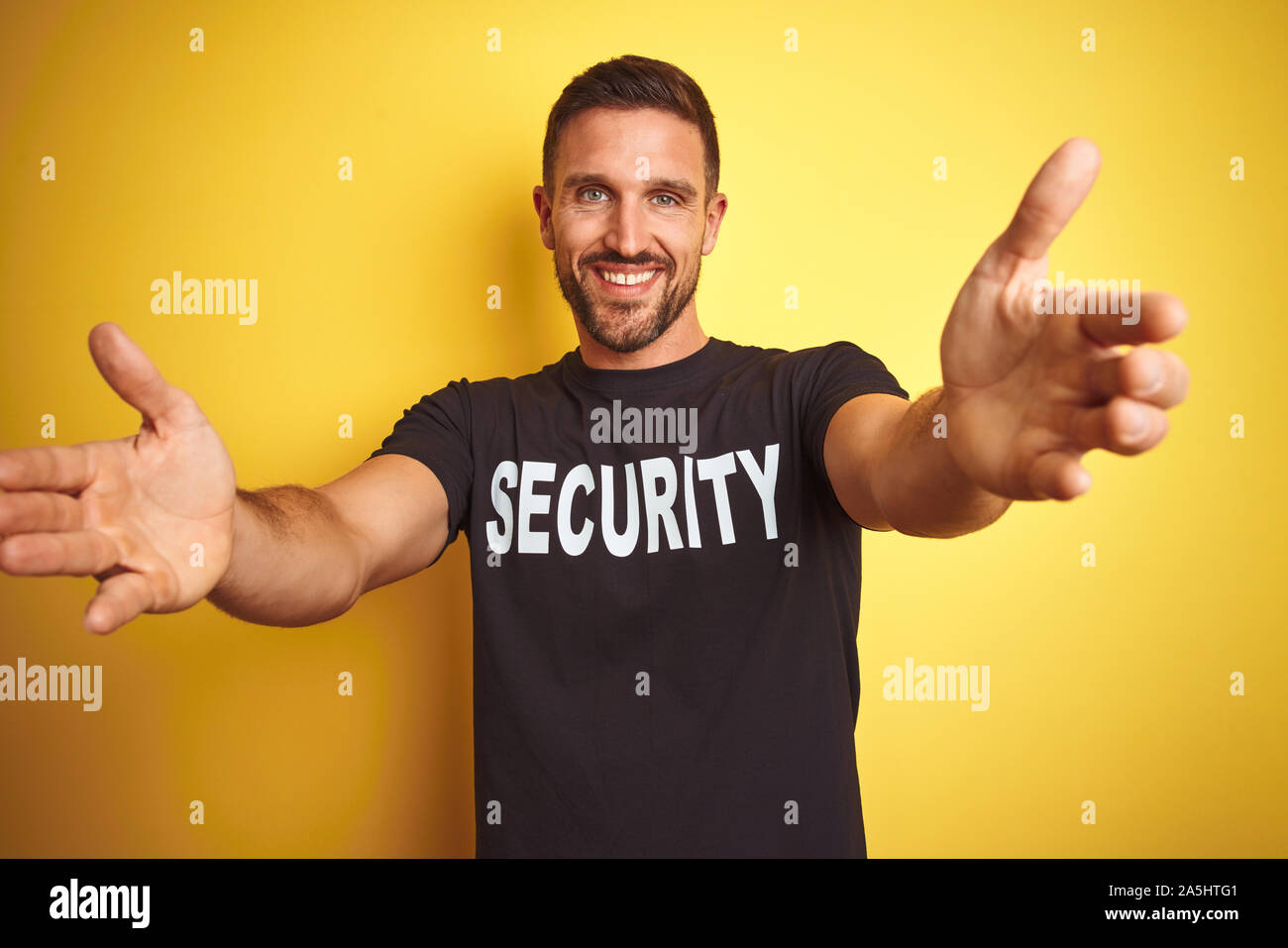Young safeguard man wearing security uniform over yellow isolated ...