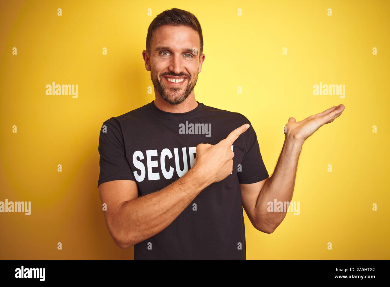 Young safeguard man wearing security uniform over yellow isolated ...