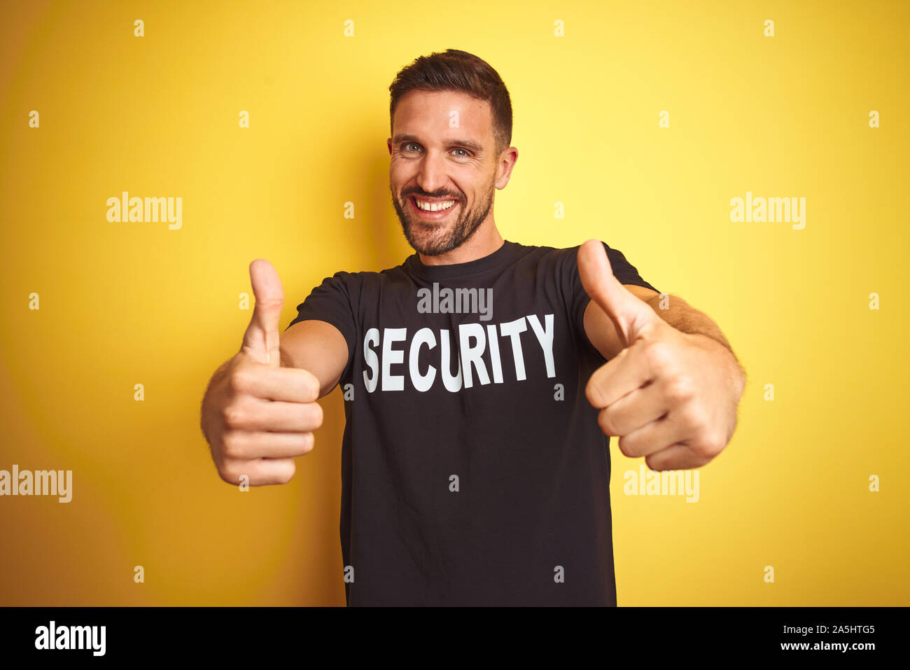Young safeguard man wearing security uniform over yellow isolated ...
