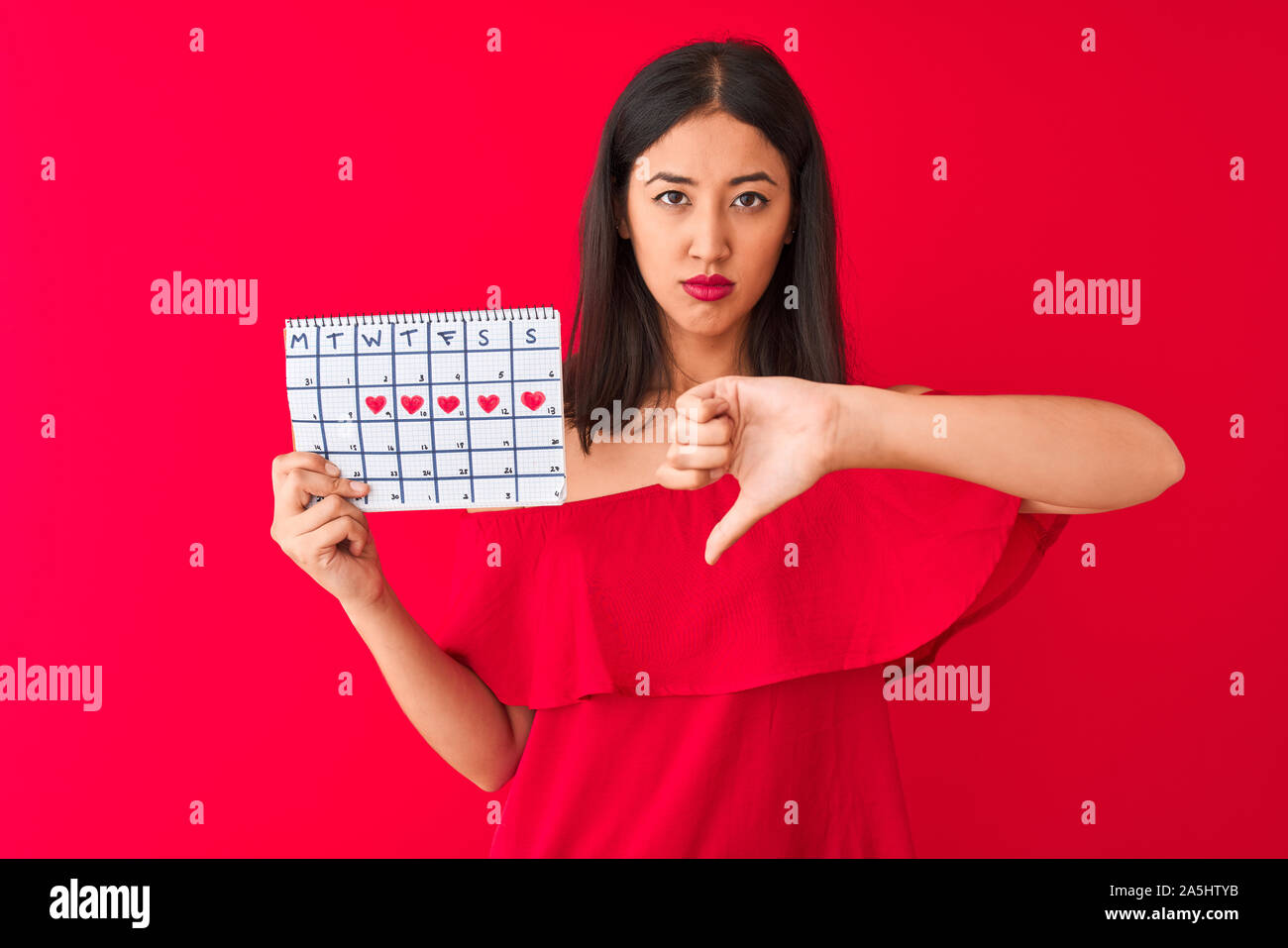 Young beautiful chinese woman holding period calendar standing over ...