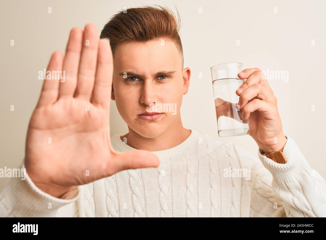 Young handsome man drinking glass of water standing over isolated white ...
