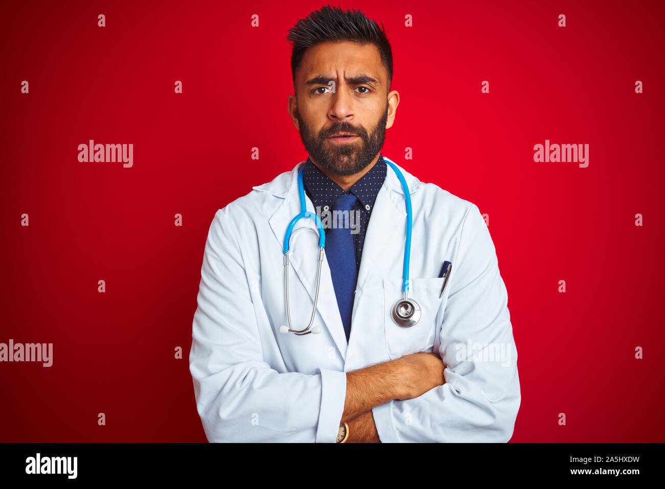 Young indian doctor man wearing stethoscope standing over isolated red ...