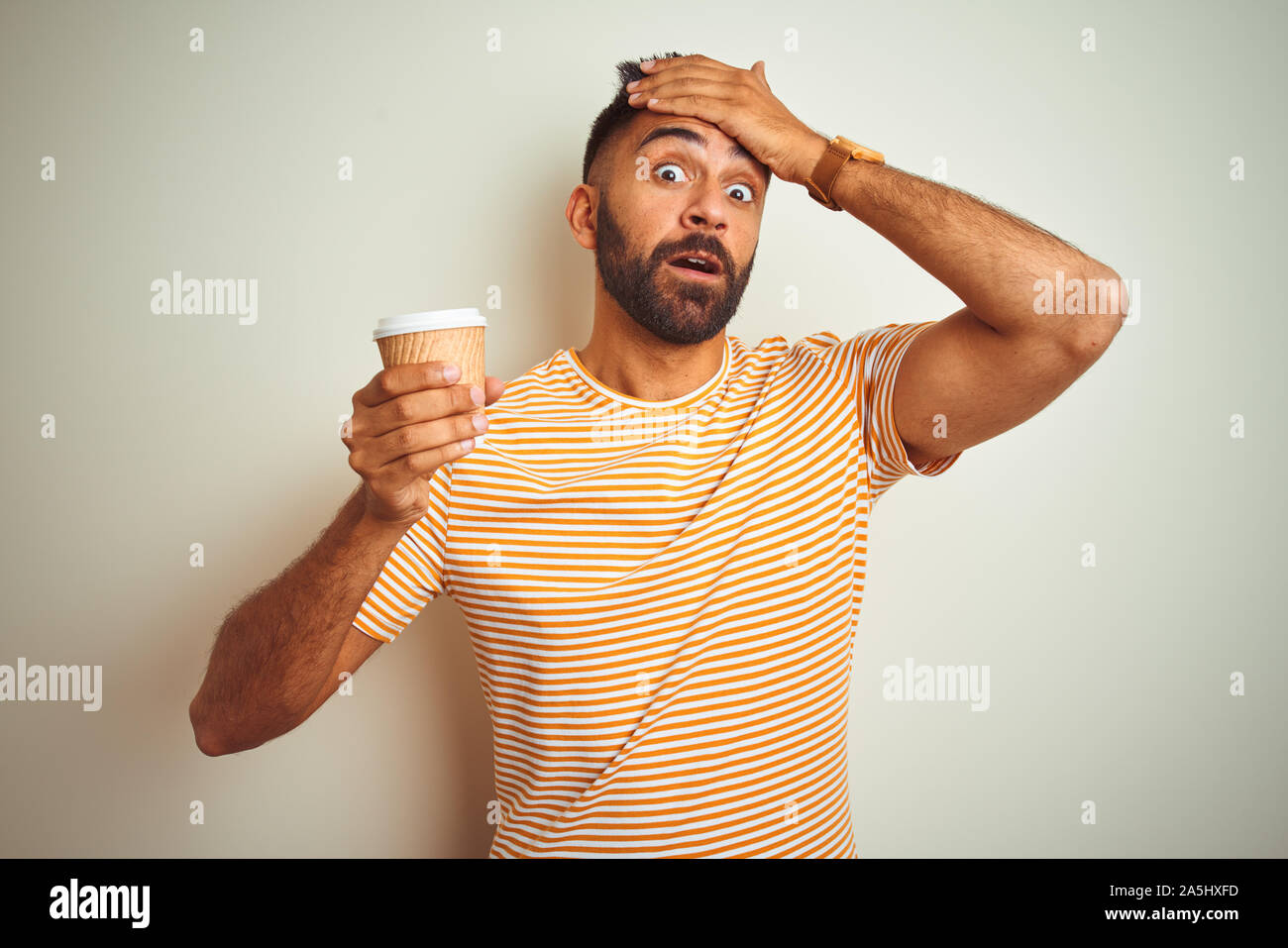 Young indian man drinking cup of coffee standing over isolated white ...