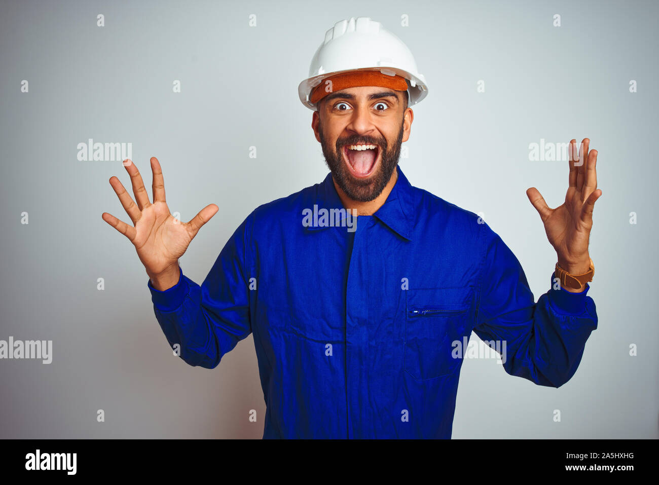 Handsome indian worker man wearing uniform and helmet over isolated ...