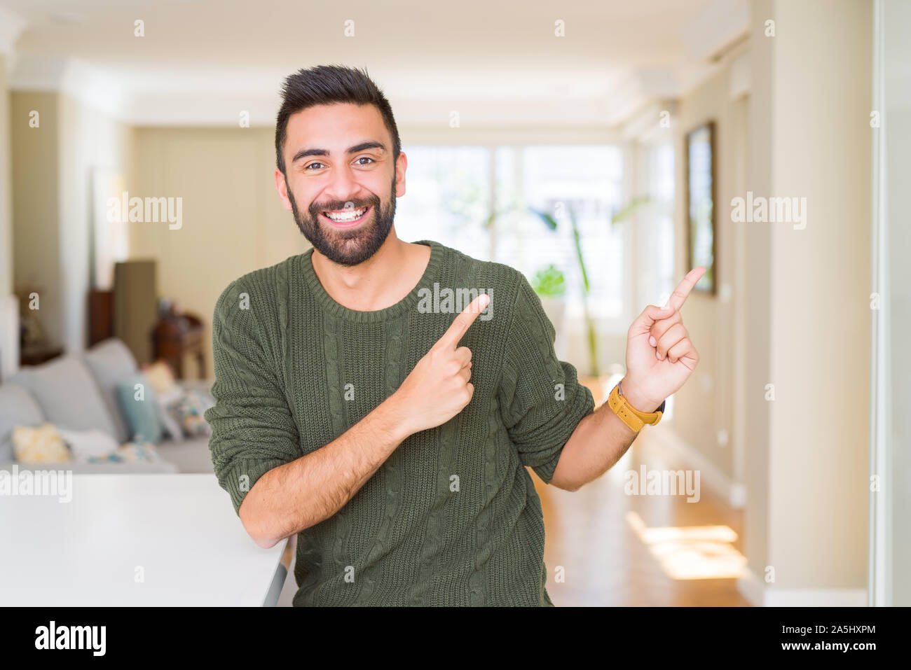 Handsome man pointing with arms and fingers, smiling cheerful with big ...
