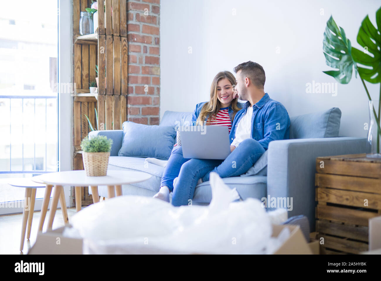 Young couple relaxing sitting on the sofa using the computer laptop ...