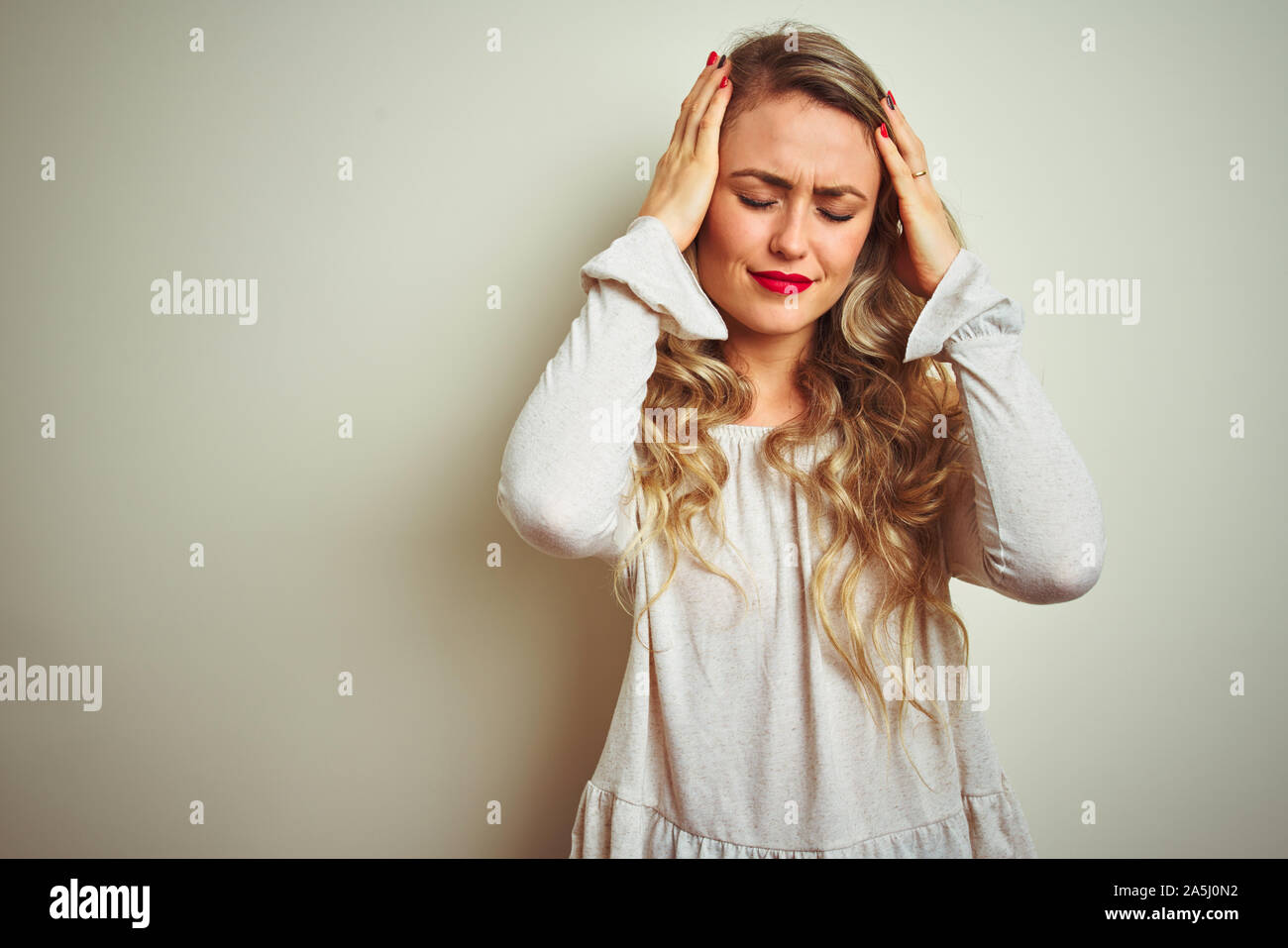 Young beautiful woman standing over white isolated background suffering ...