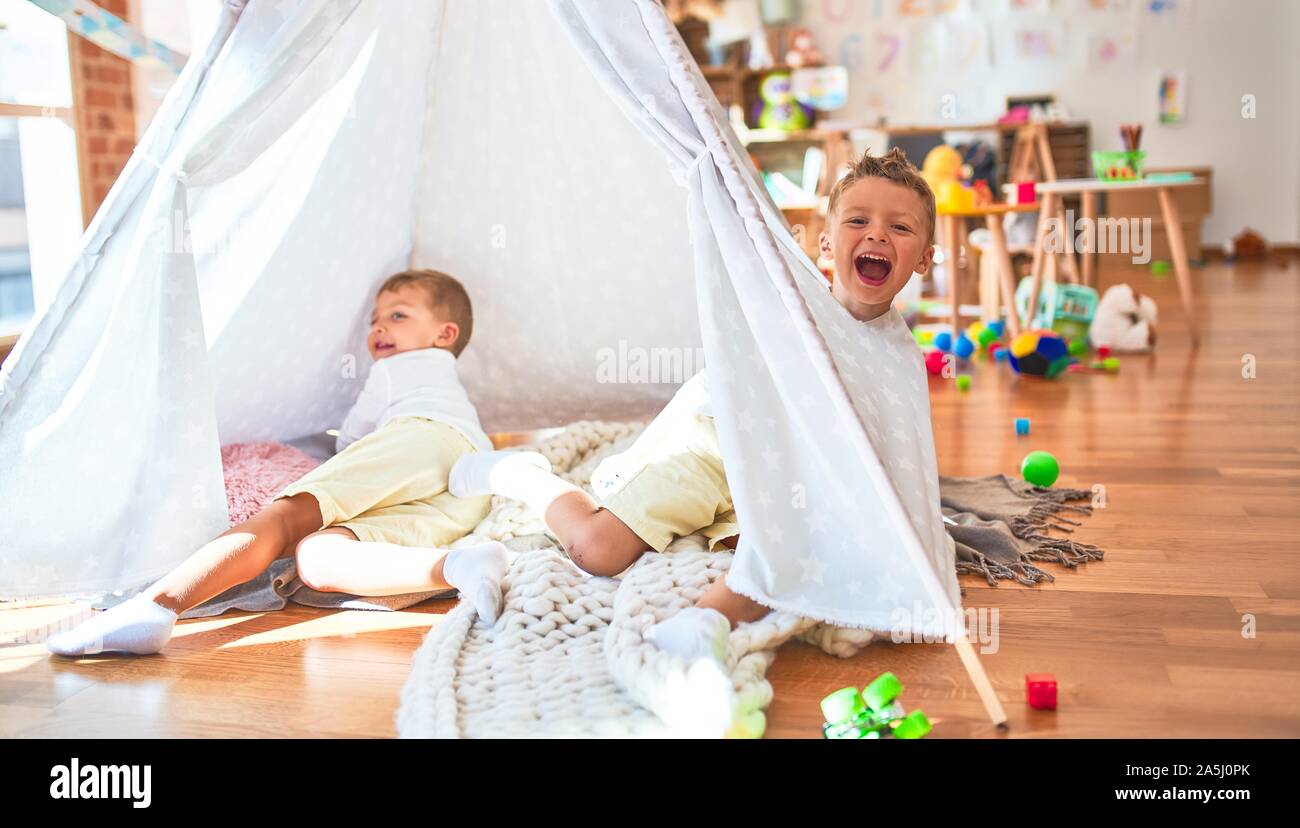 Adorable blonde twins playing inside tipi around lots of toys at ...