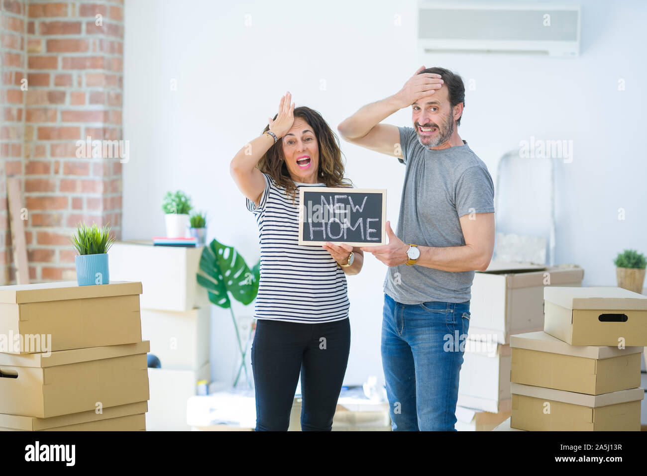 Middle age senior couple holding blackboard moving to a new home ...