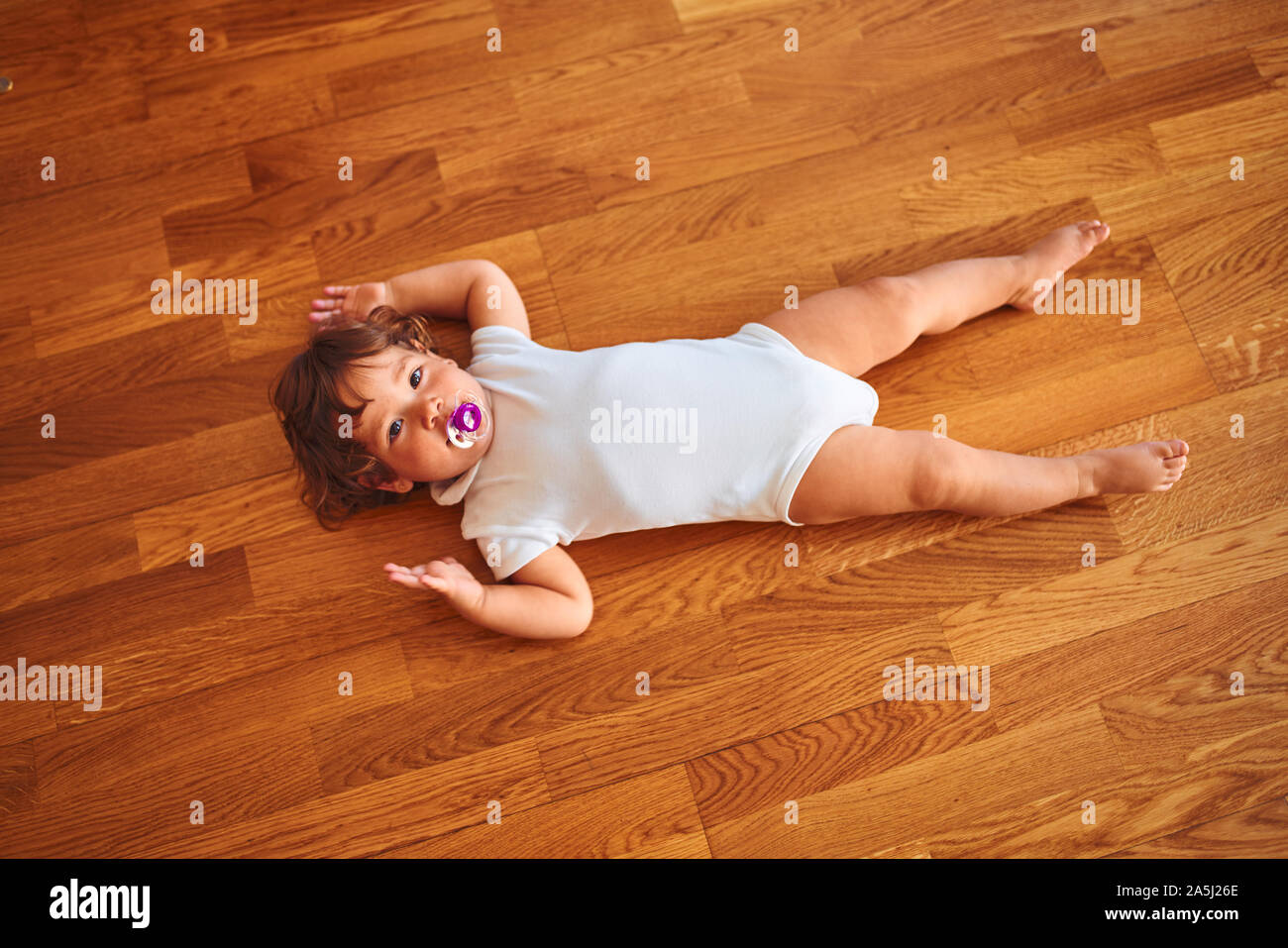 Beautiful toddler child girl wearing white bodysuit lying down on the ...