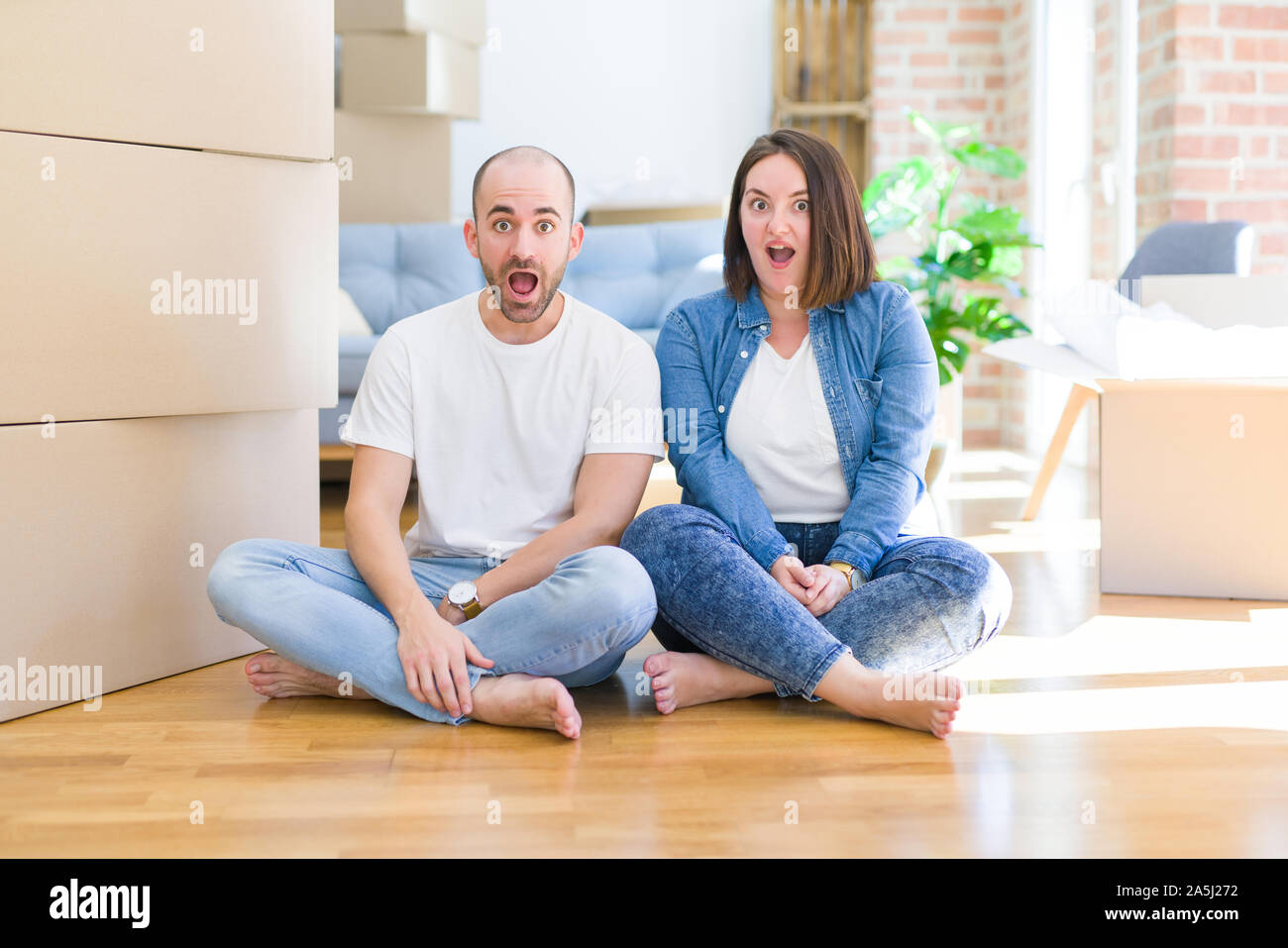 Young couple sitting on the floor arround cardboard boxes moving to a ...