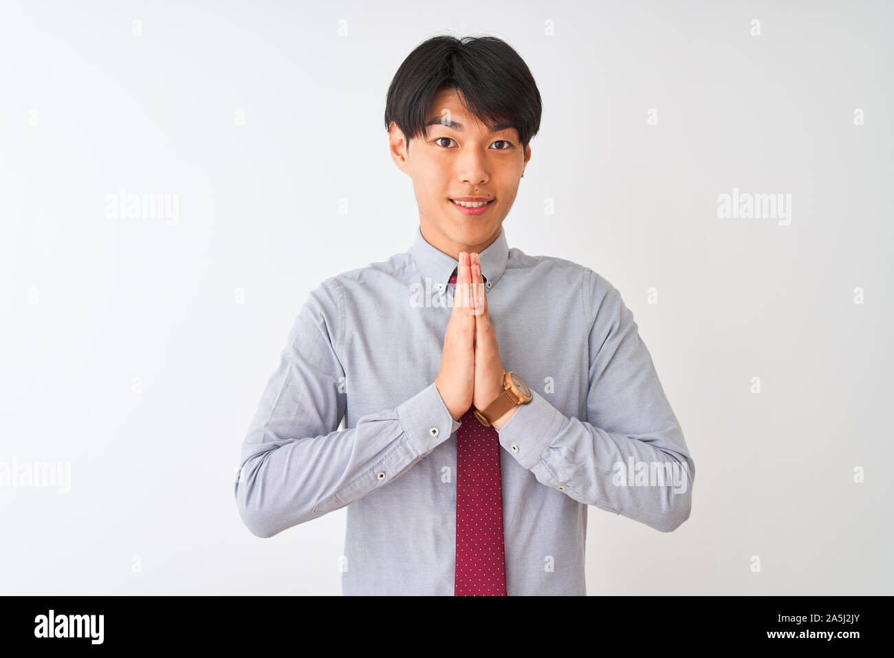 Chinese businessman wearing elegant tie standing over isolated white background praying with ...
