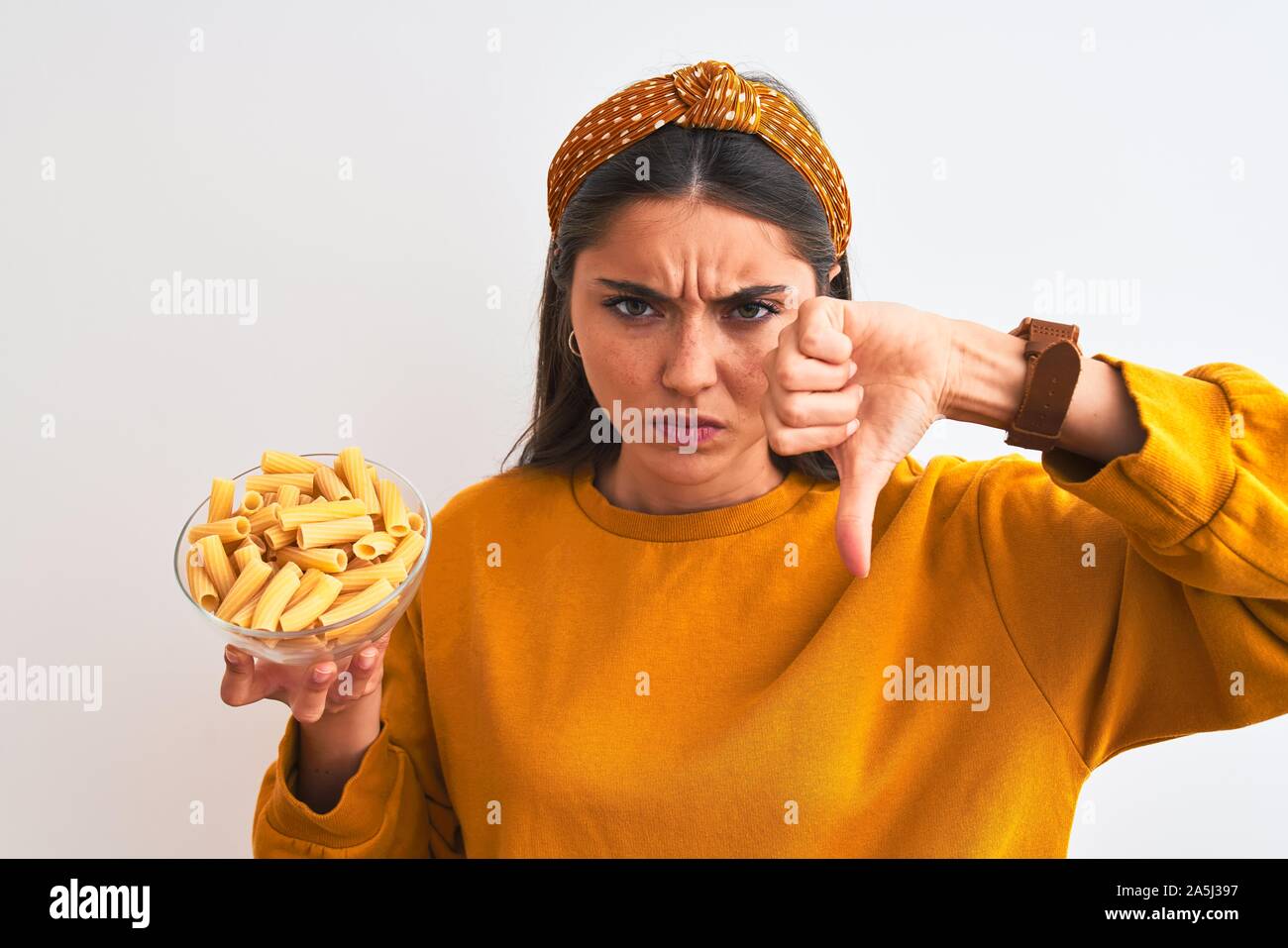 Young beautiful woman holding bowl with macaroni pasta over isolated ...
